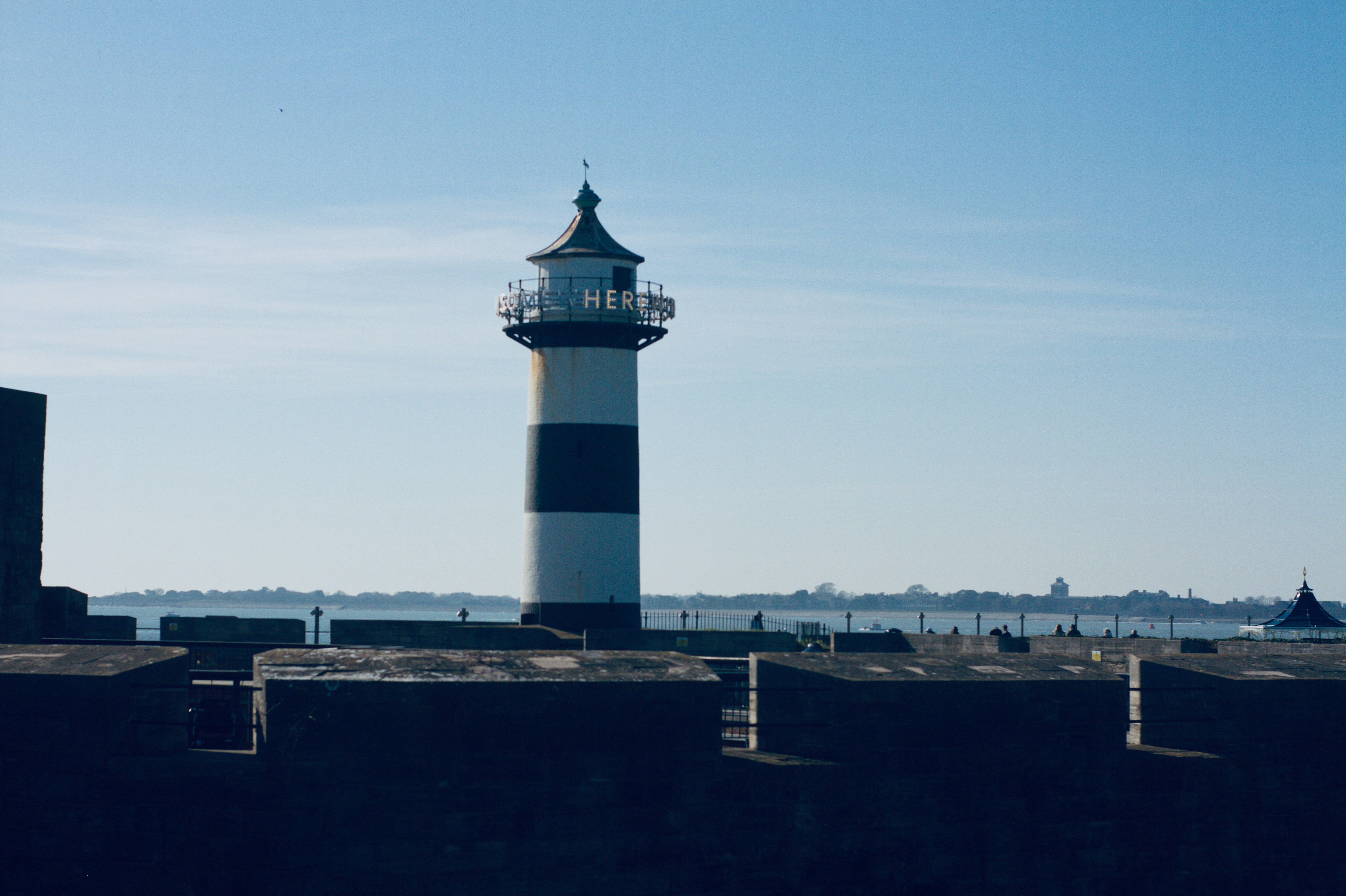 Beacon of Blue: The Striped Lighthouse Amid Quiet Breakwater