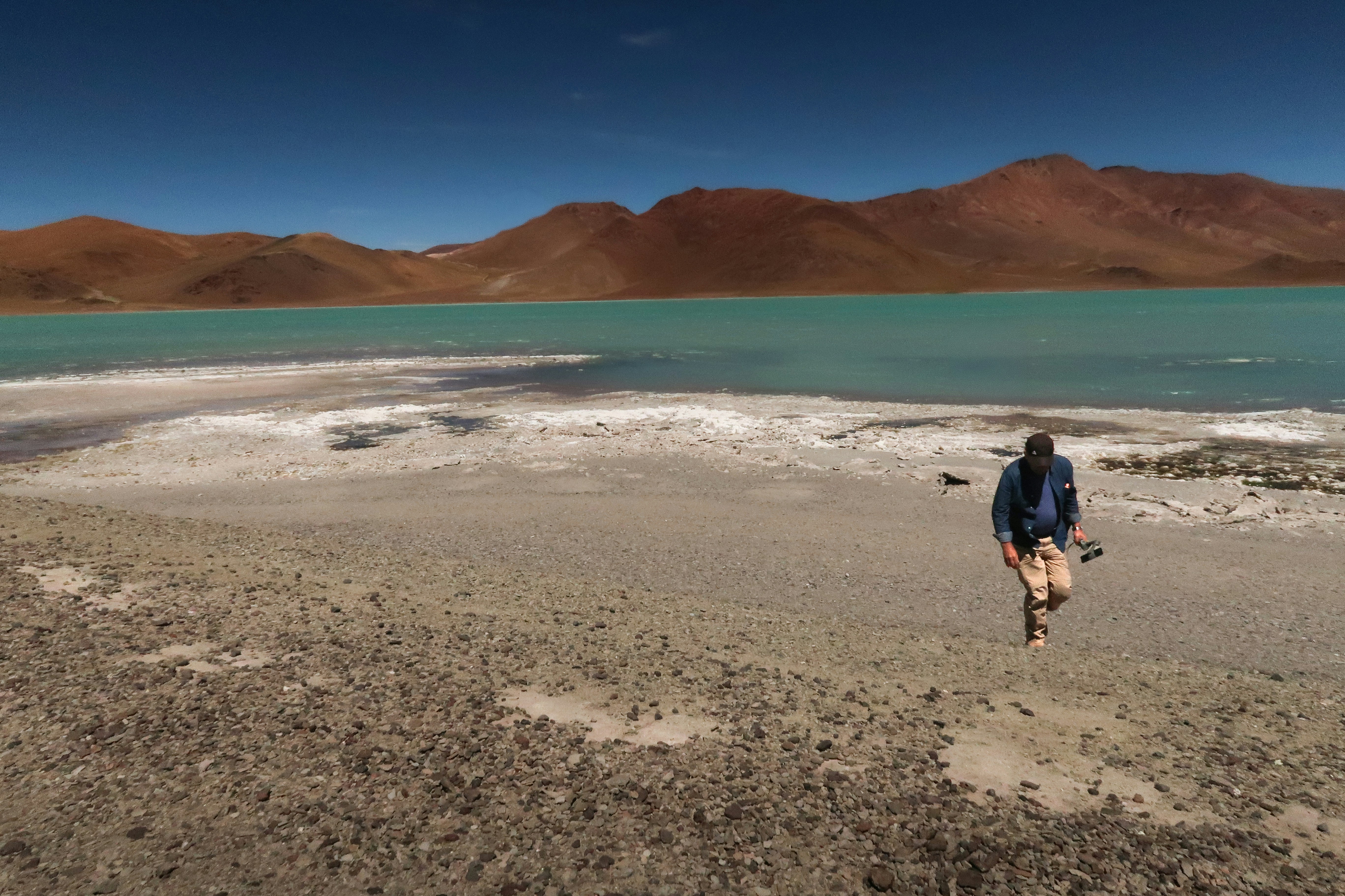 Runner by a Turquoise Shore Under a Rugged Red Ridge
