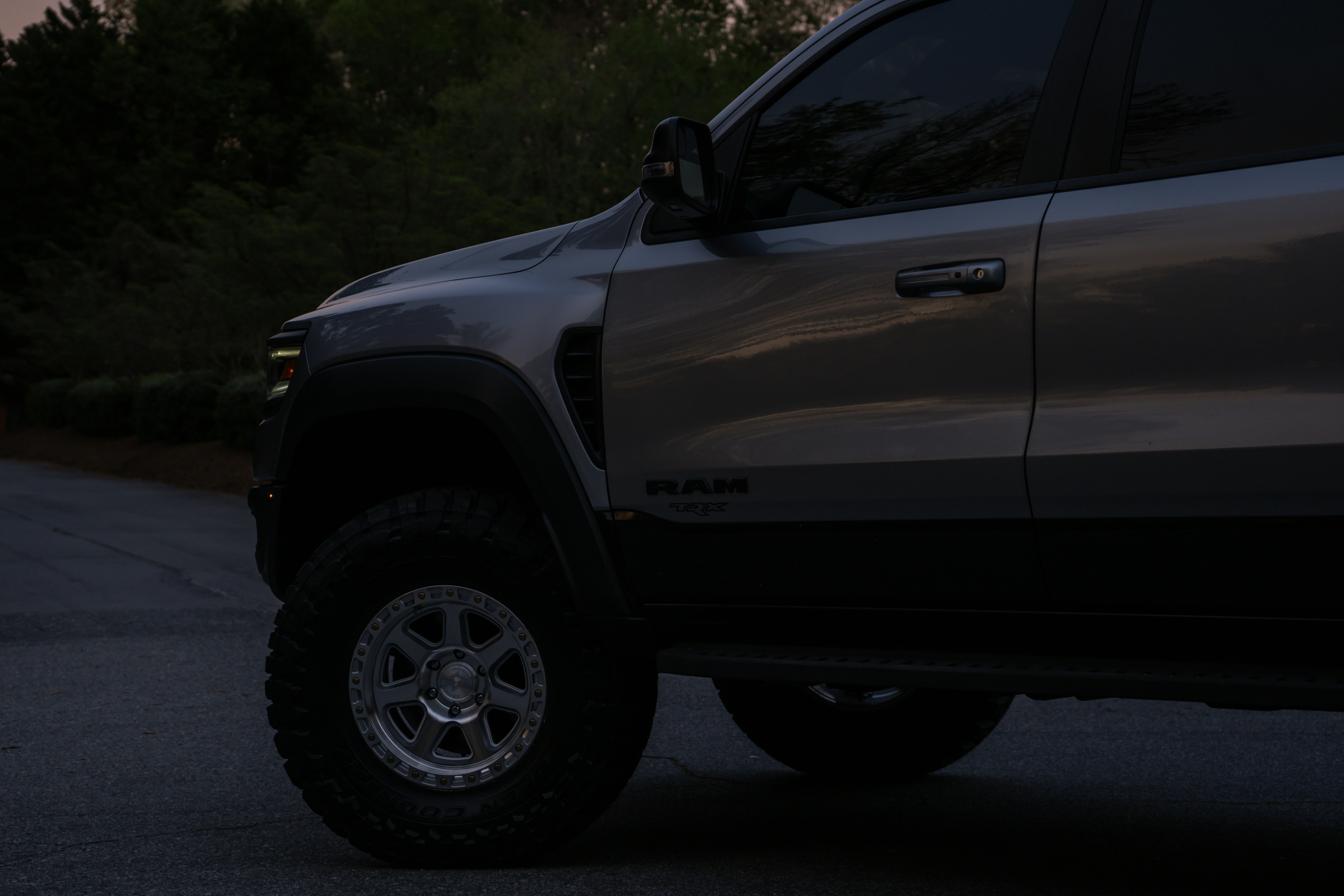 Shadowed Front Wheel Well: A Close-Subject of a Mud-Treaded Pickup