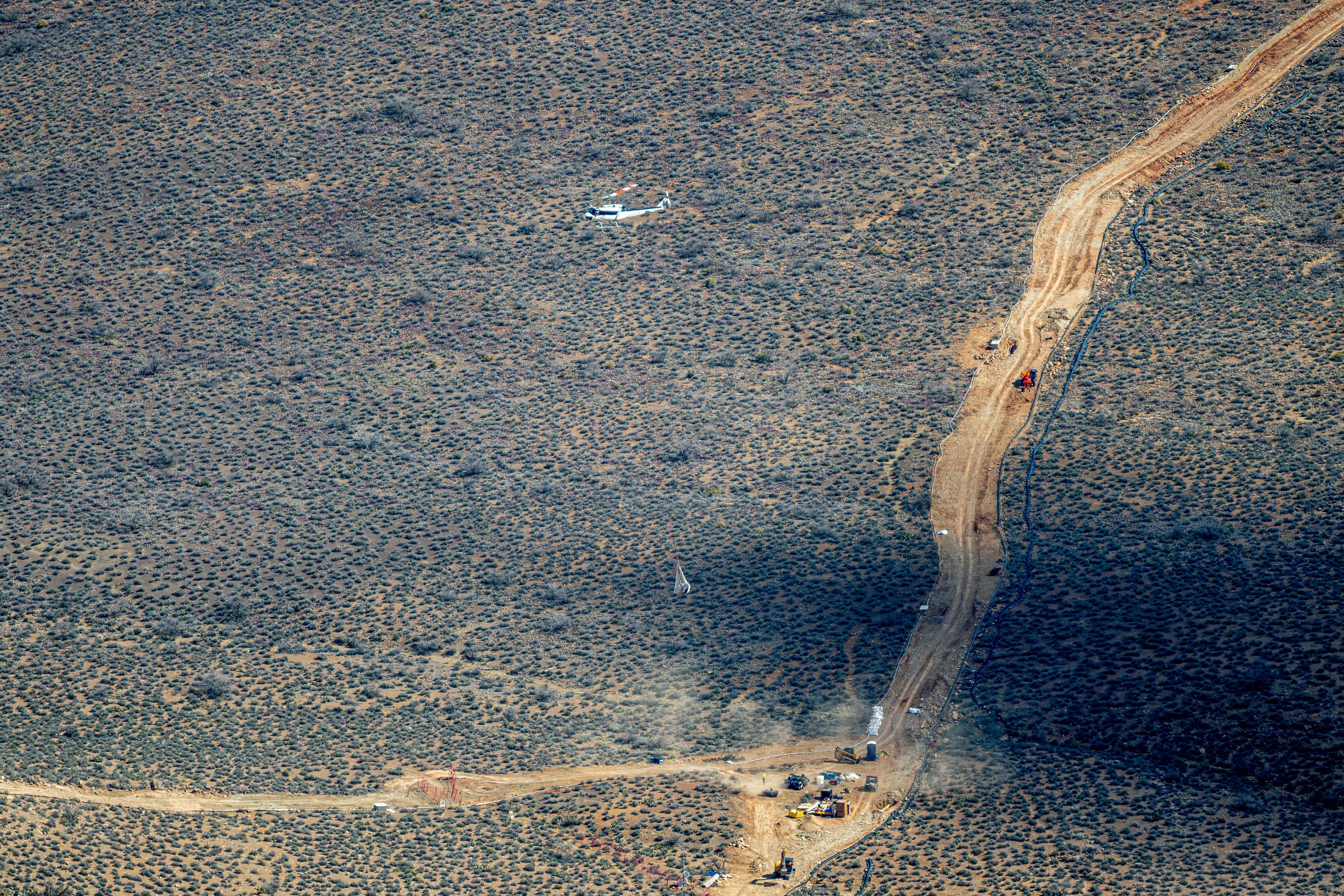 Dusty Road Traces through a Desert Ridge as an Aircraft Circles Above