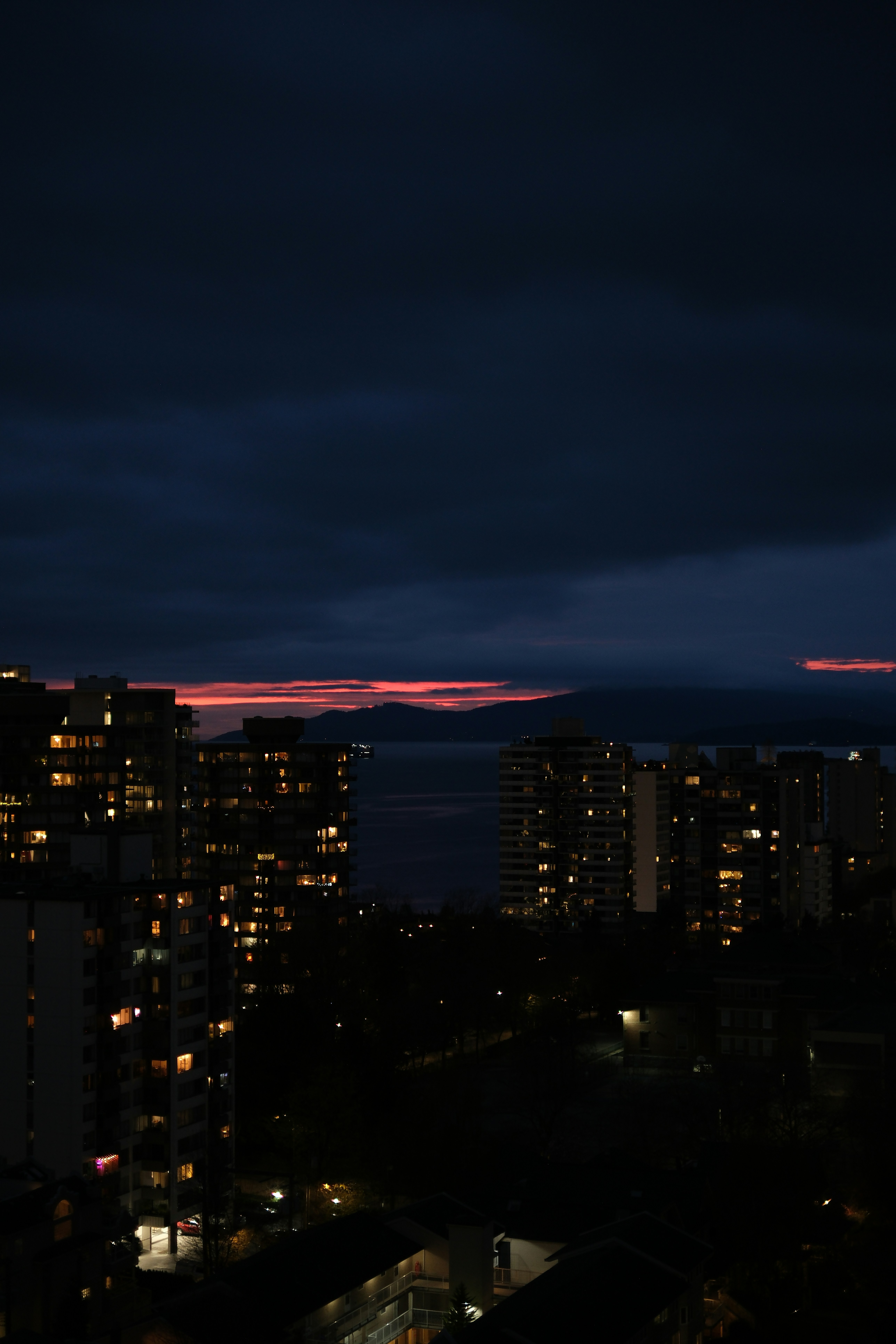 Twilight Skyline: City Lights Against a Narrow Red Horizon