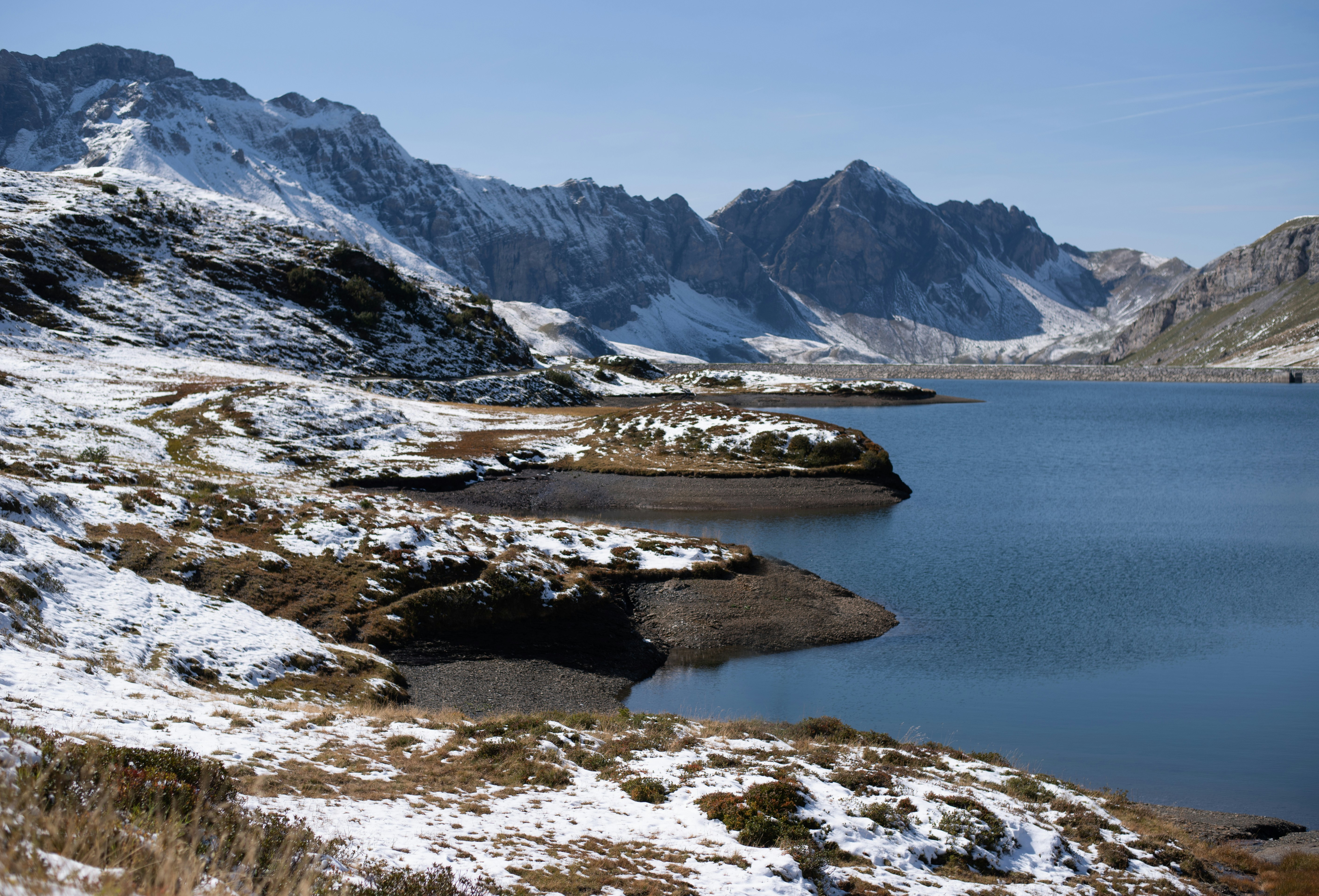 Snow-kissed shoreline under jagged alpine peaks