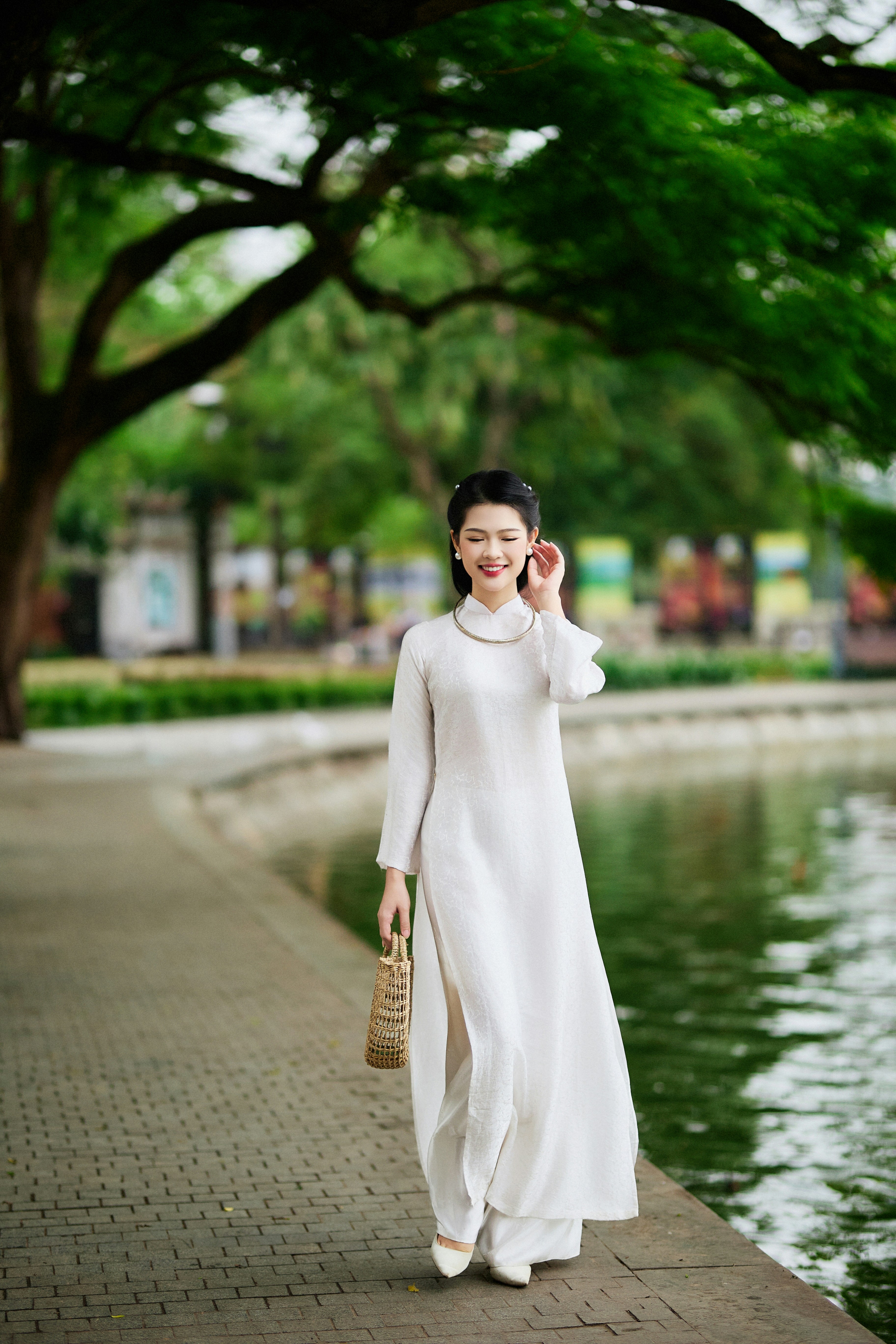 Graceful walk by the pond: a white áo dài in a tranquil park