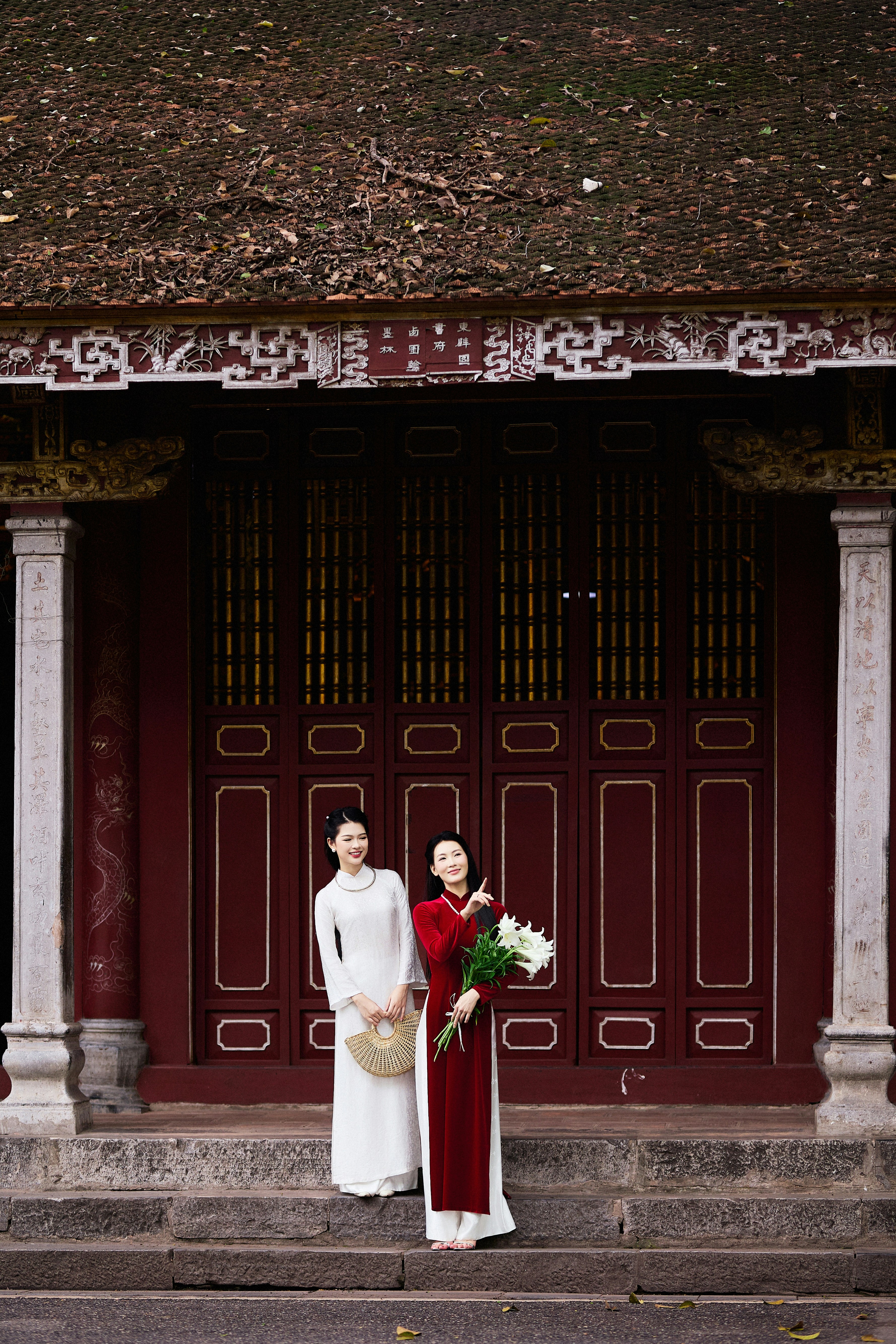 Two Women in Traditional Dress Stand Guard at an Ornate Red Doorway