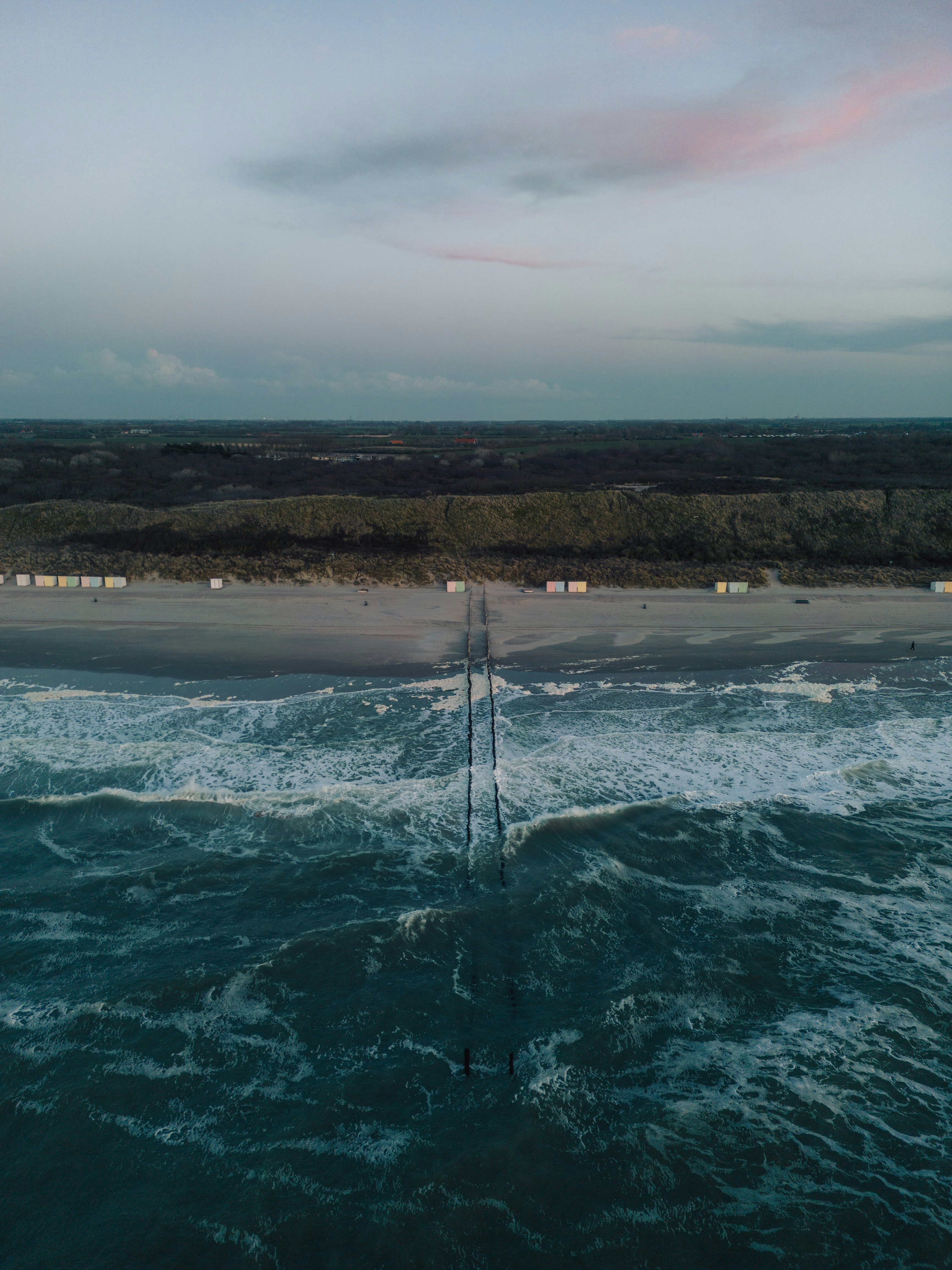 Coastal Pier Cut: Aerial View Over Breakers toward Distant Dunes