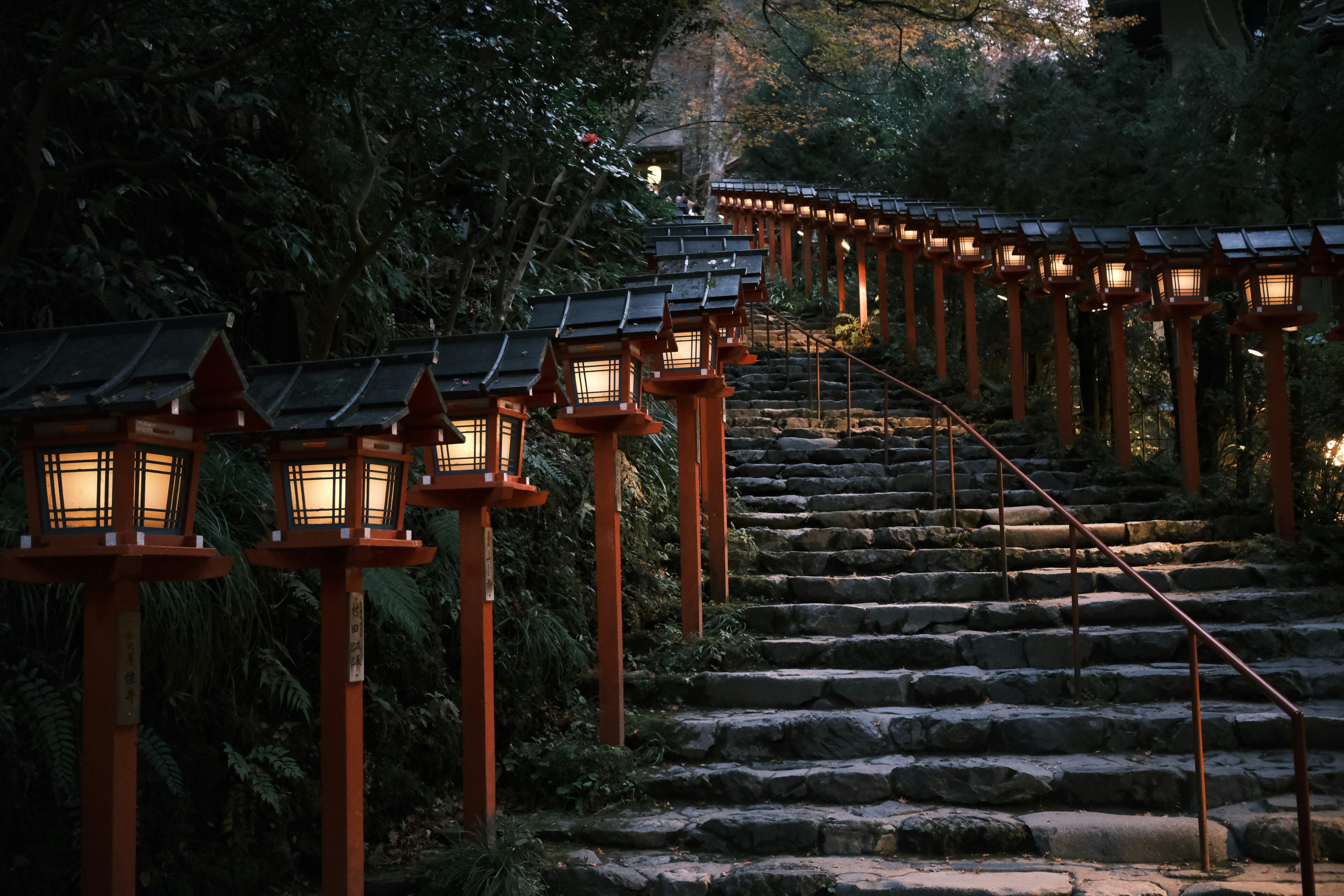 Lantern-lit ascent: stone steps under a corridor of guardian lamps