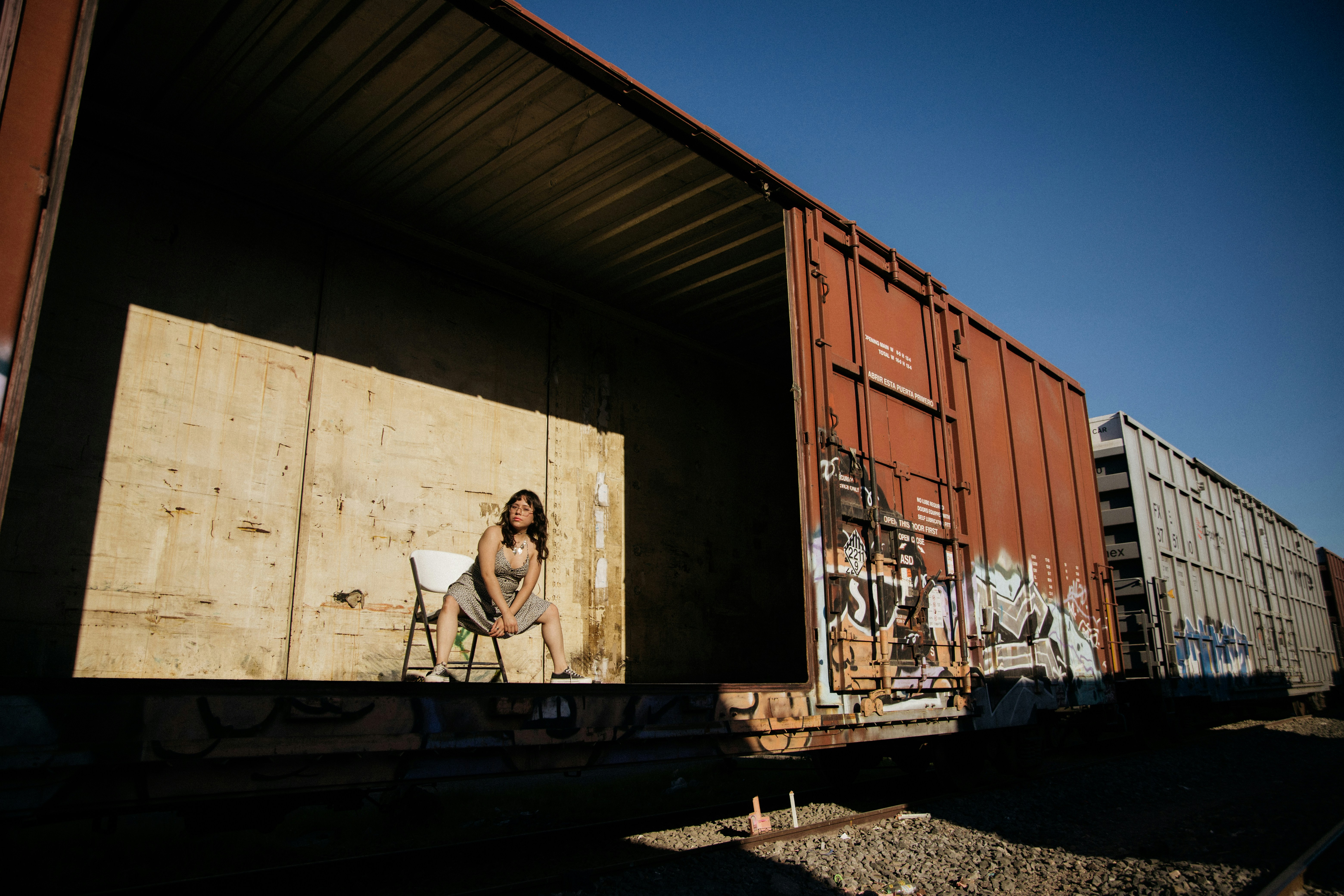 Portrait Amid Giants: A Woman Seated in a Railroad Car Opens a Quiet Moment