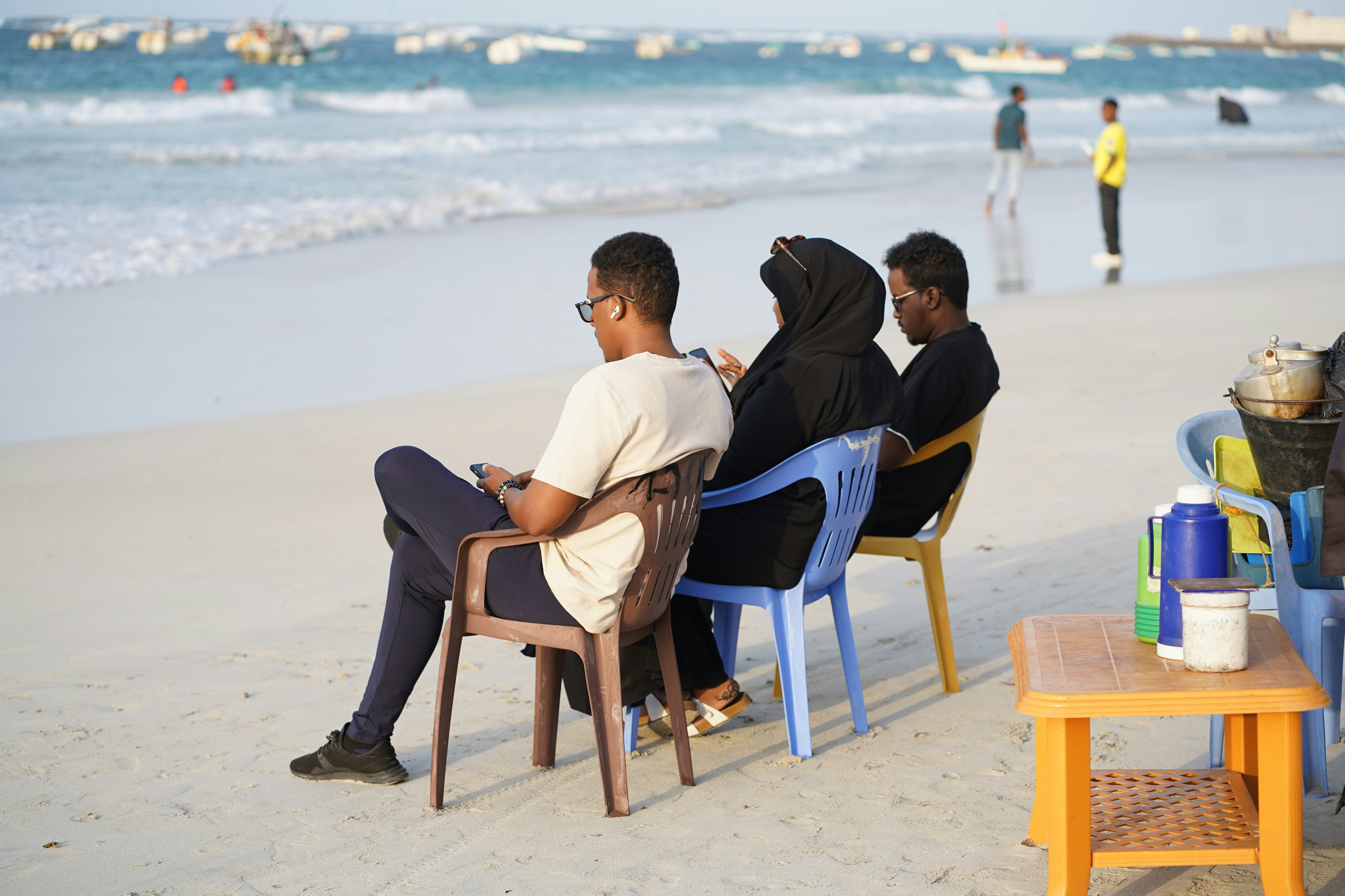 Sunlit Beach View: Friends Share a Quiet Moment by the Sea