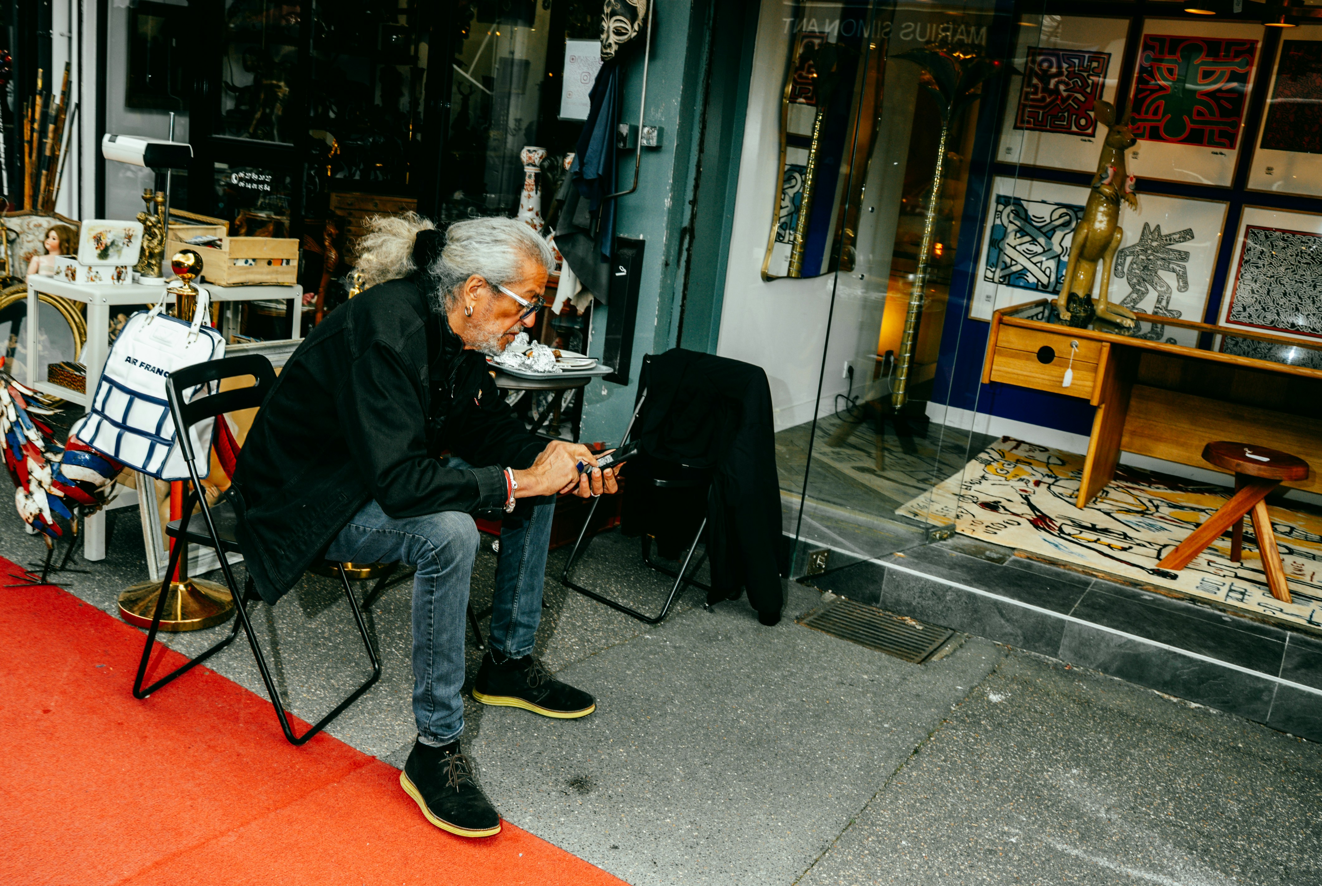 Street-side Artistry: An Elderly Man Sketching in Front of a Gallery