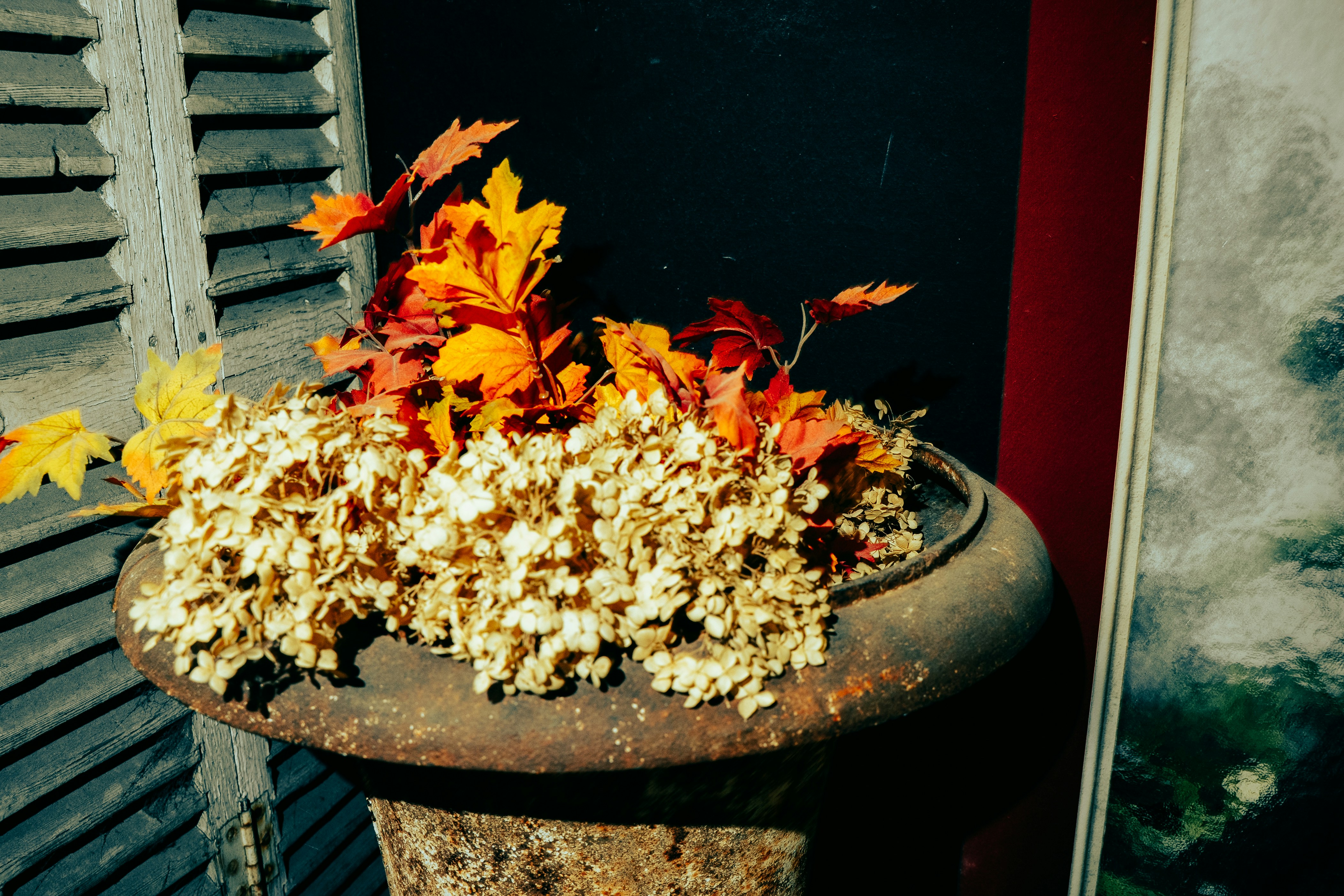 Autumn bouquets in a rustic urn against weathered shutters