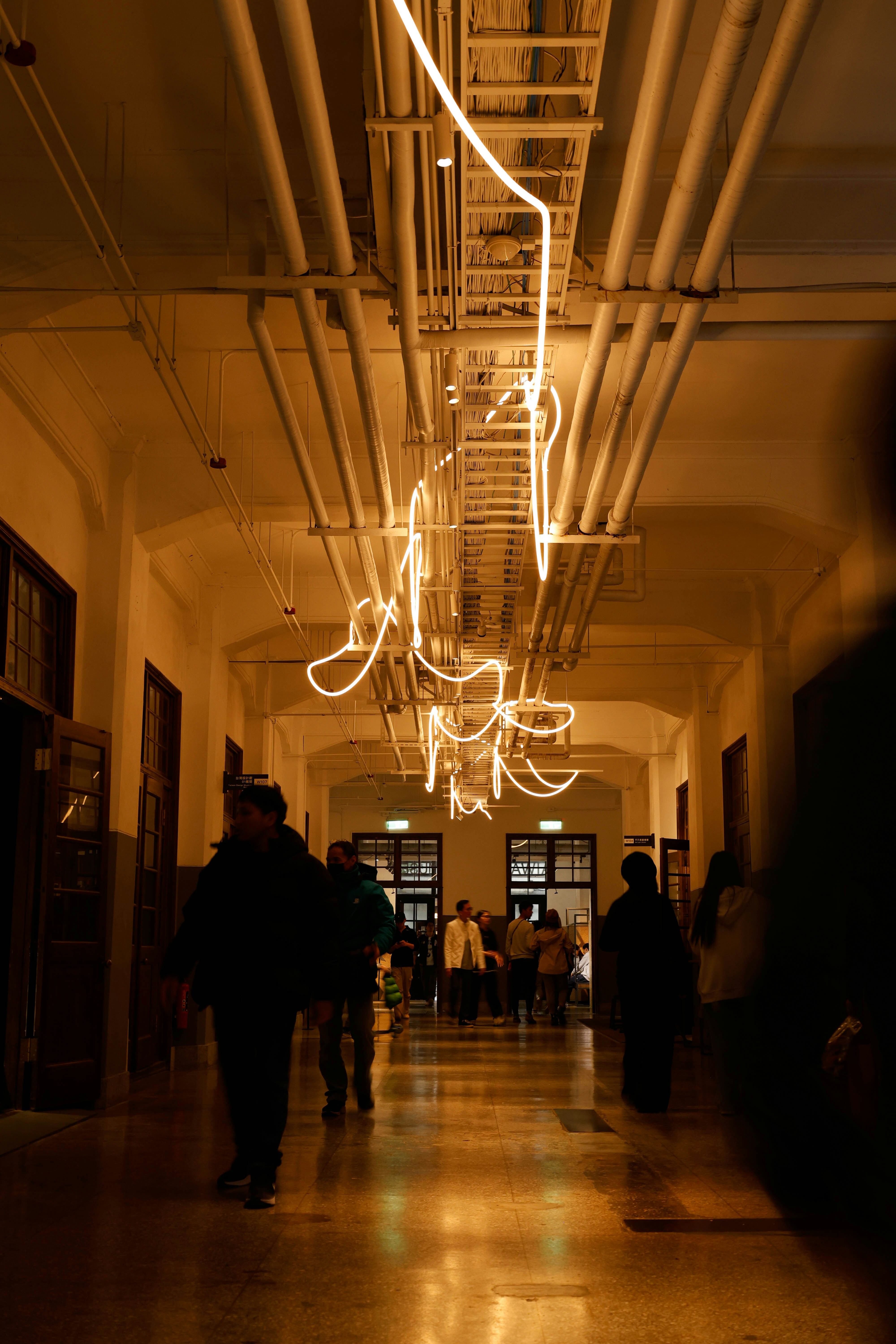 Underground Glow: People Walk Through a Warm, Neon-lit Corridor