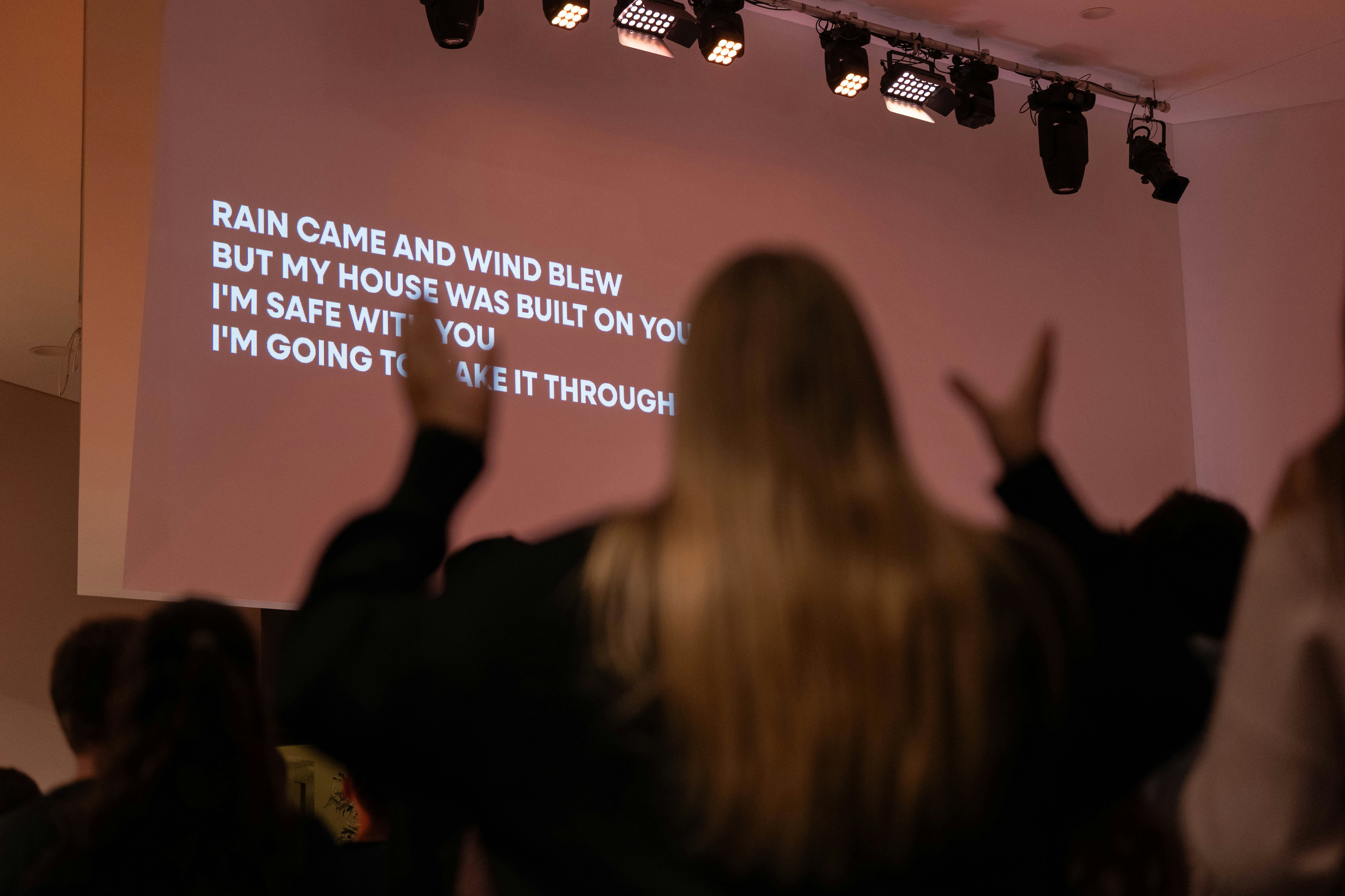 Audience in a Dim Auditorium Reading Lyrics on a Screen