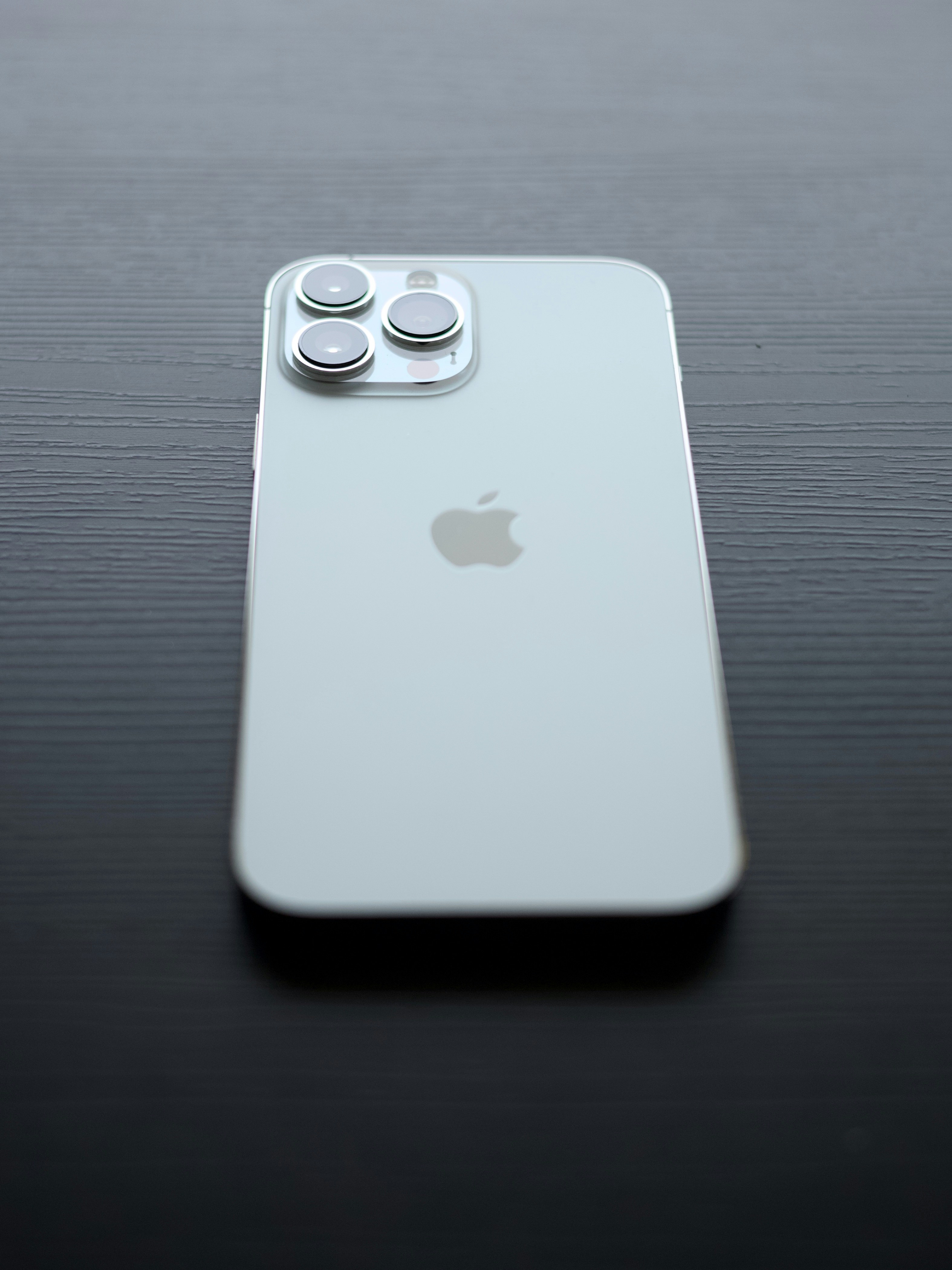 Quiet Brilliance: The Subtle Glow of a Silver iPhone Resting on Dark Wood