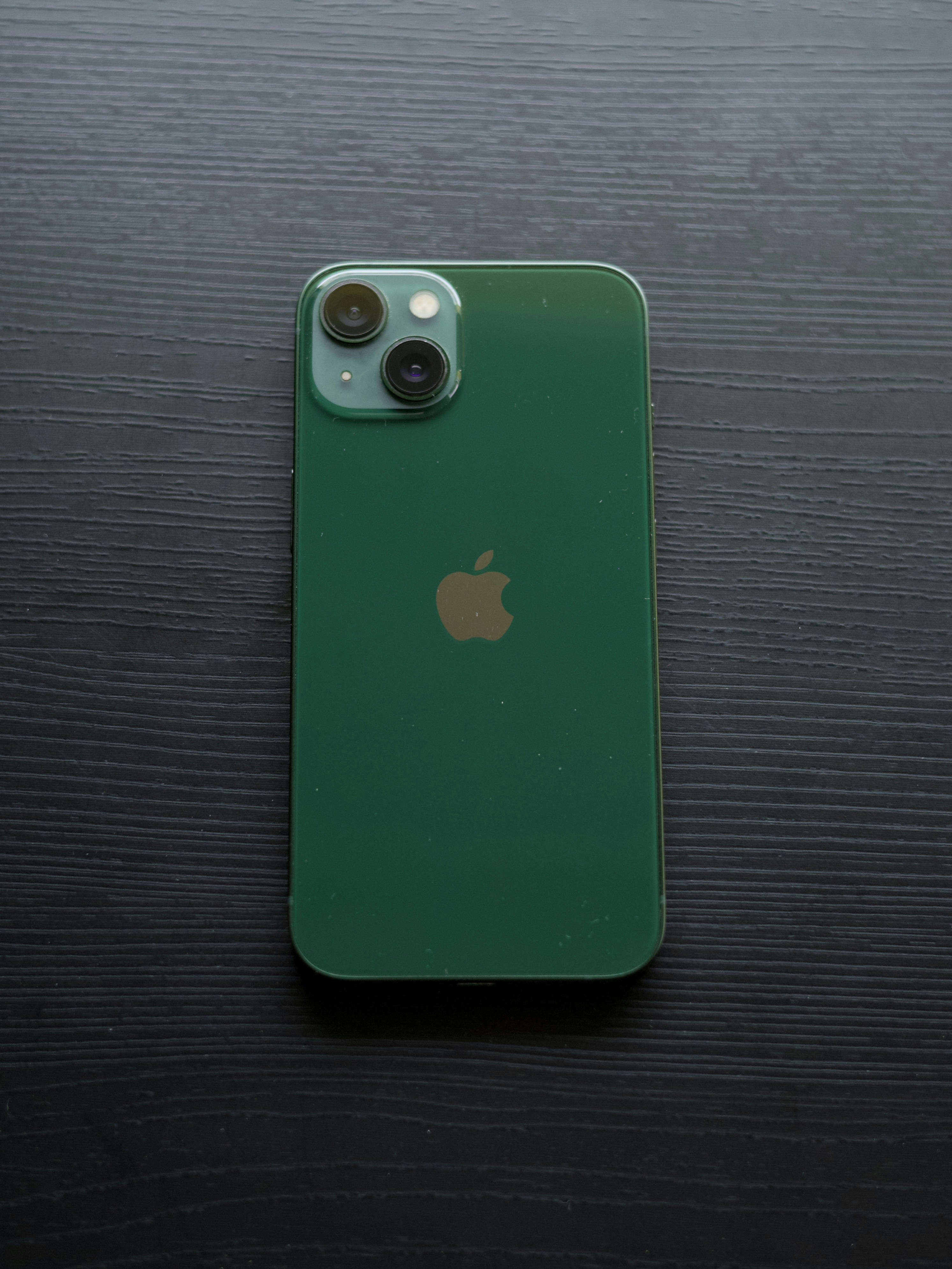Emerald back: a green iPhone resting on a dark wooden surface