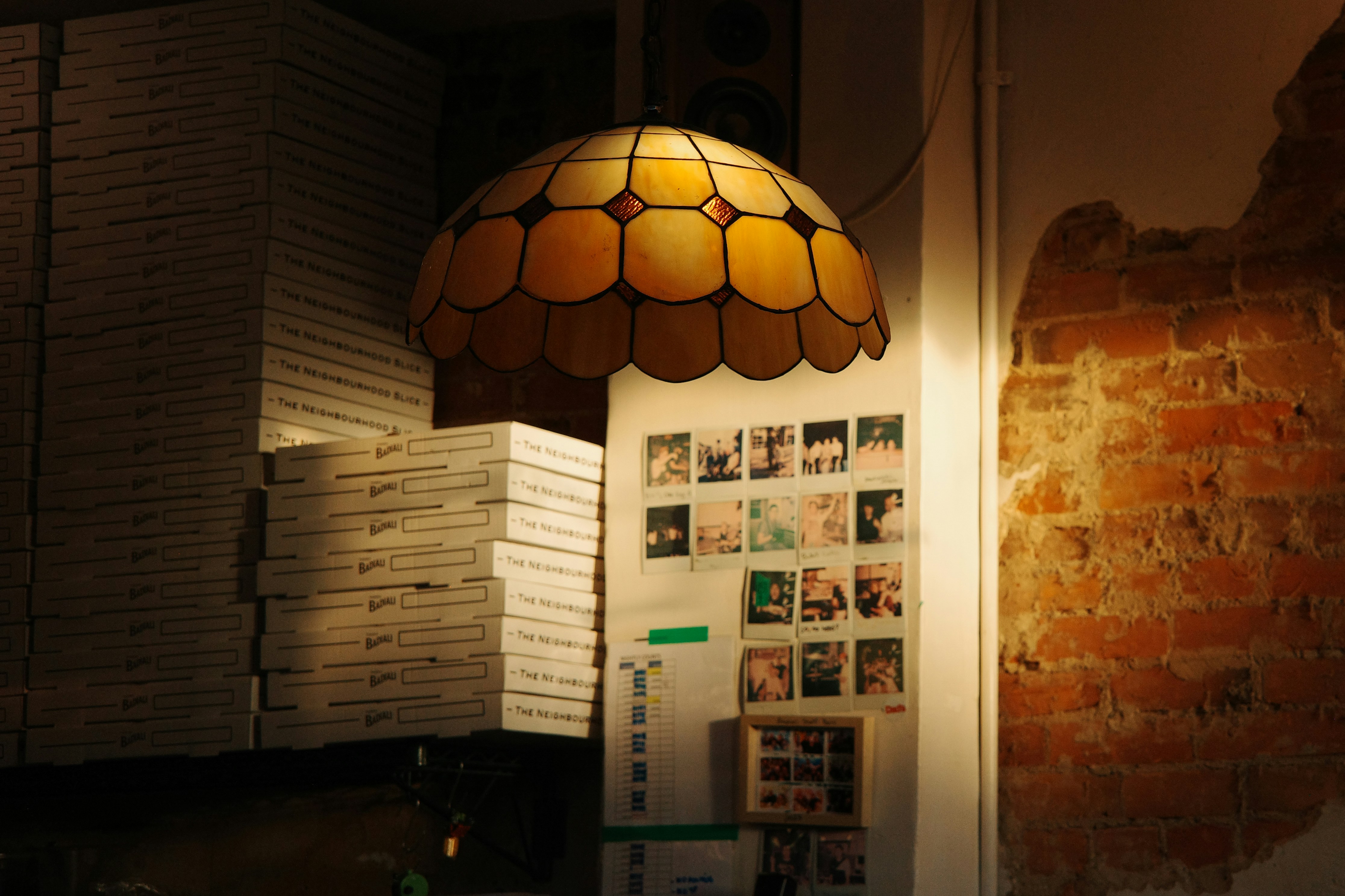 Warm amber lamp over brick and stacked boxes in a cozy workspace