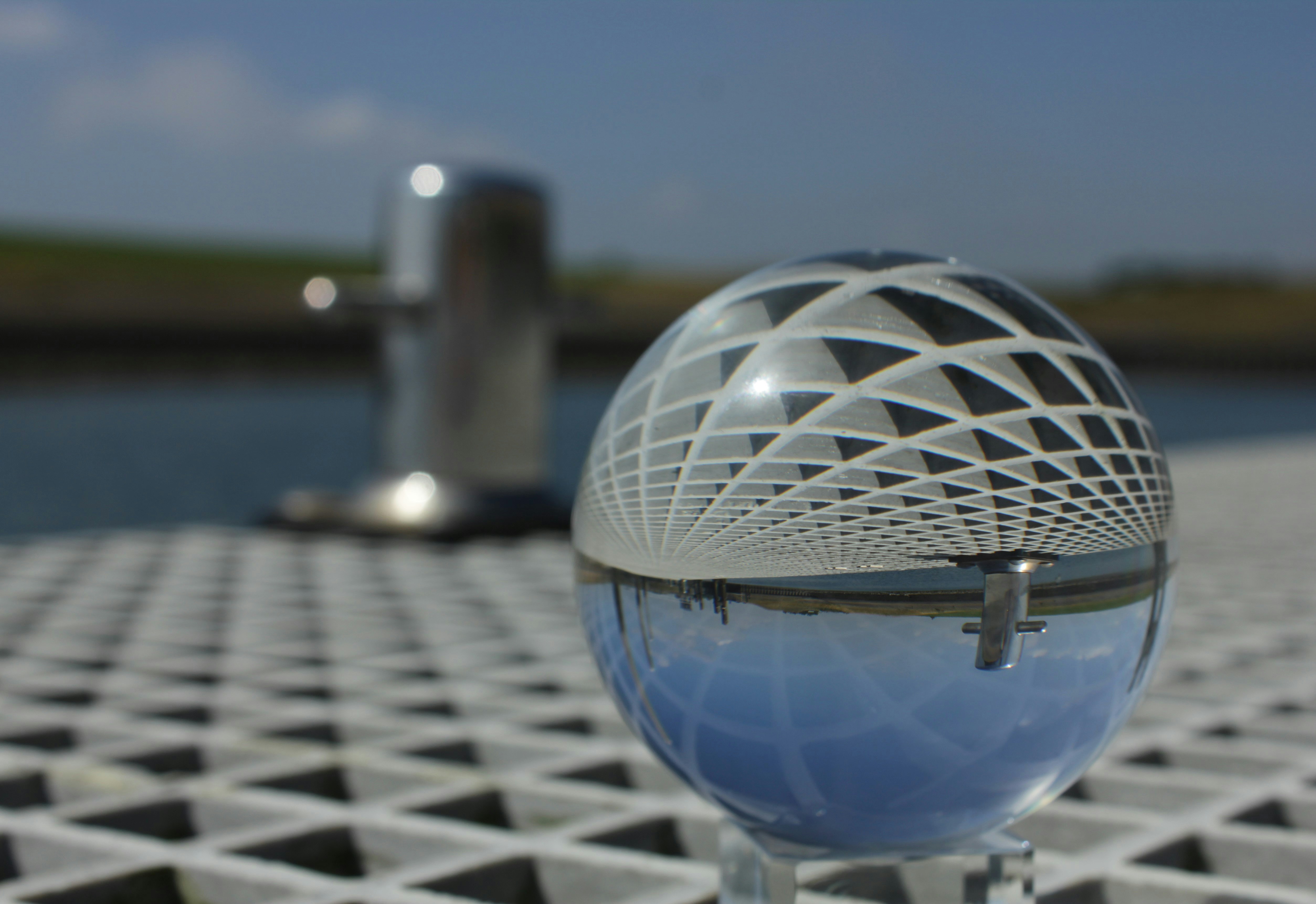 Geometric Glass Orb Reflecting a Pier and Sky