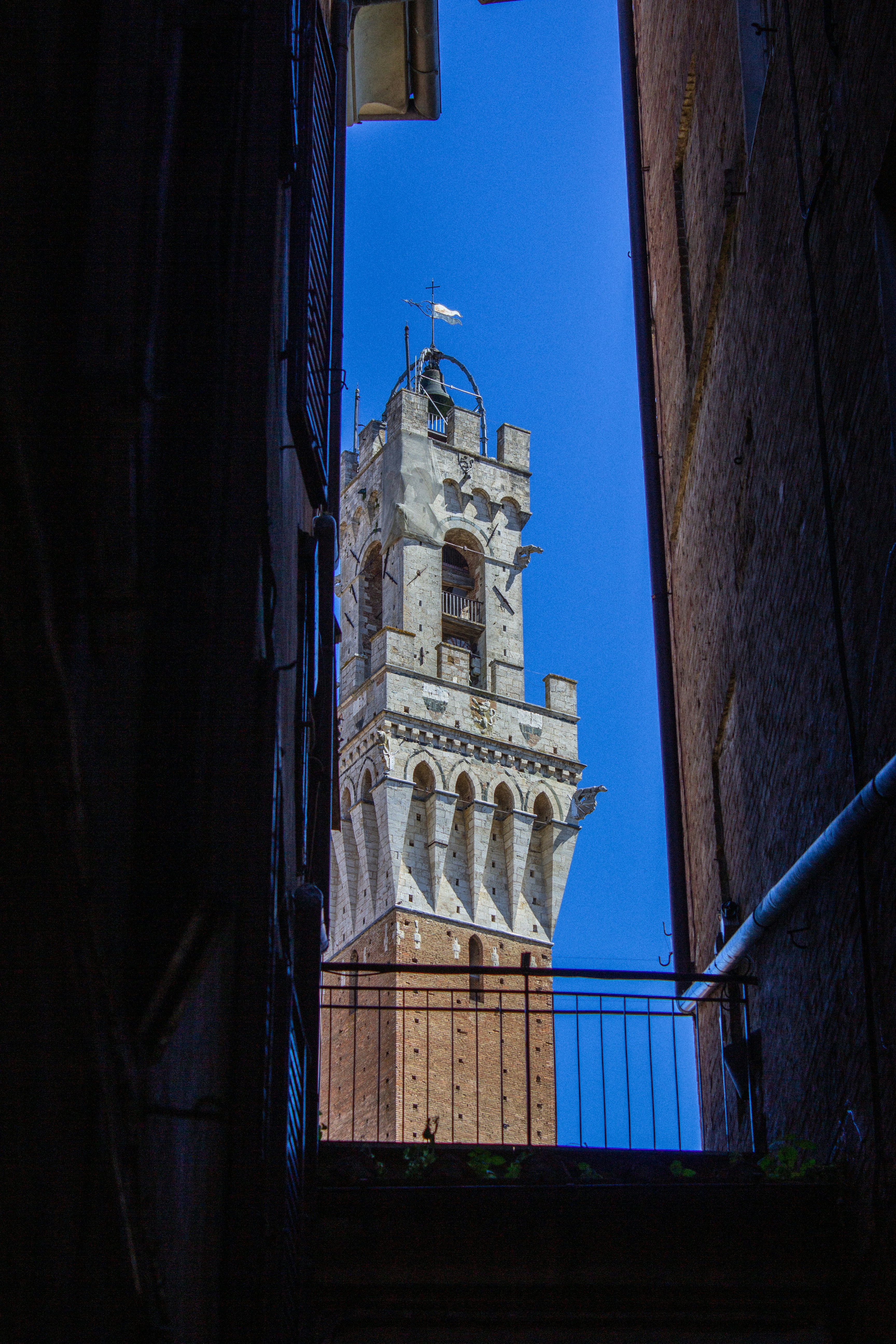 Tower in the Alley: A Narrow View Up to the Blue Sky