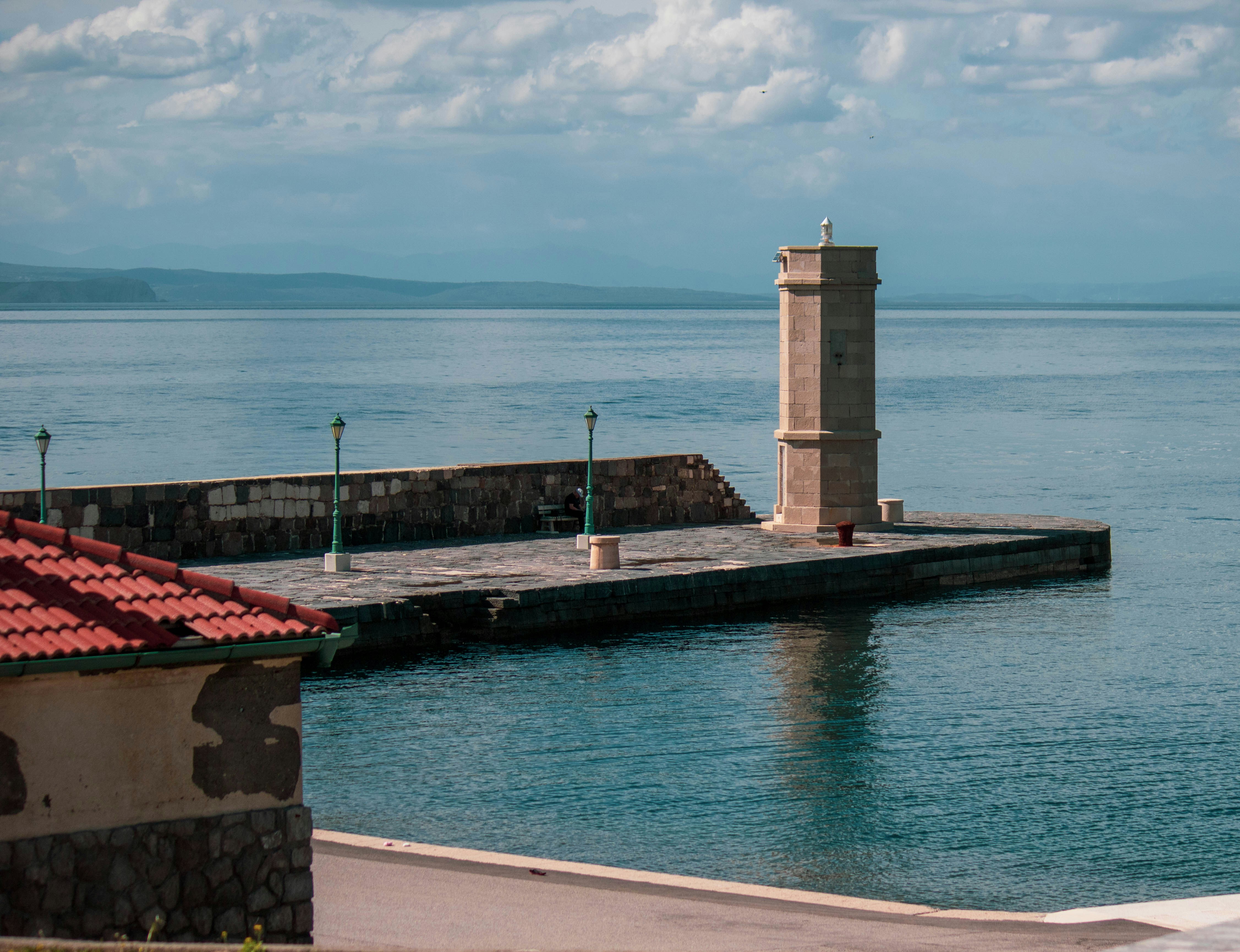 Stone Pier and lighthouse silhouette at the calm harbor
