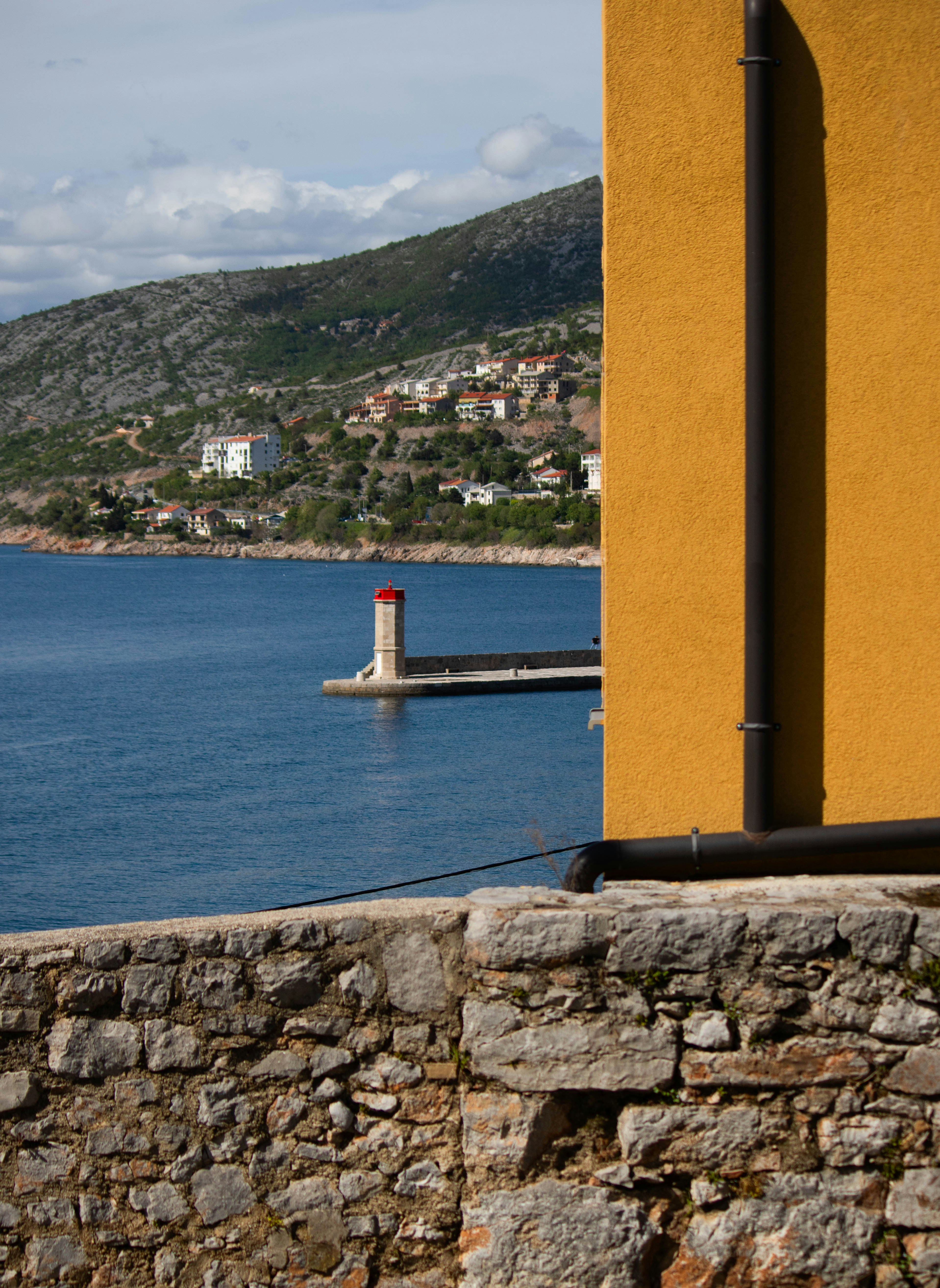 Yellow Wall and Harbor Lighthouse: A Seaside Moment