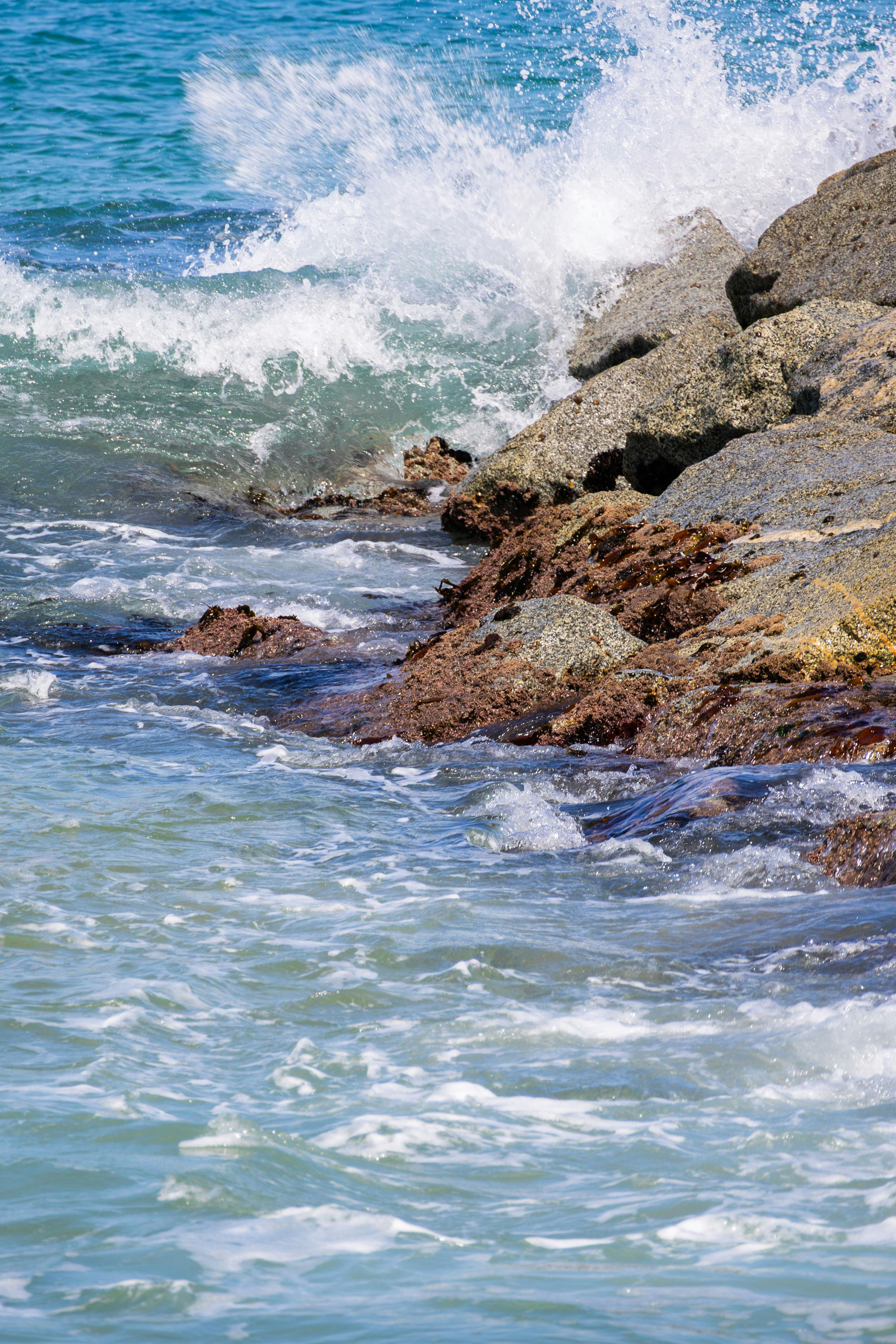Rugged shoreline: Waves colliding with sunlit rocks