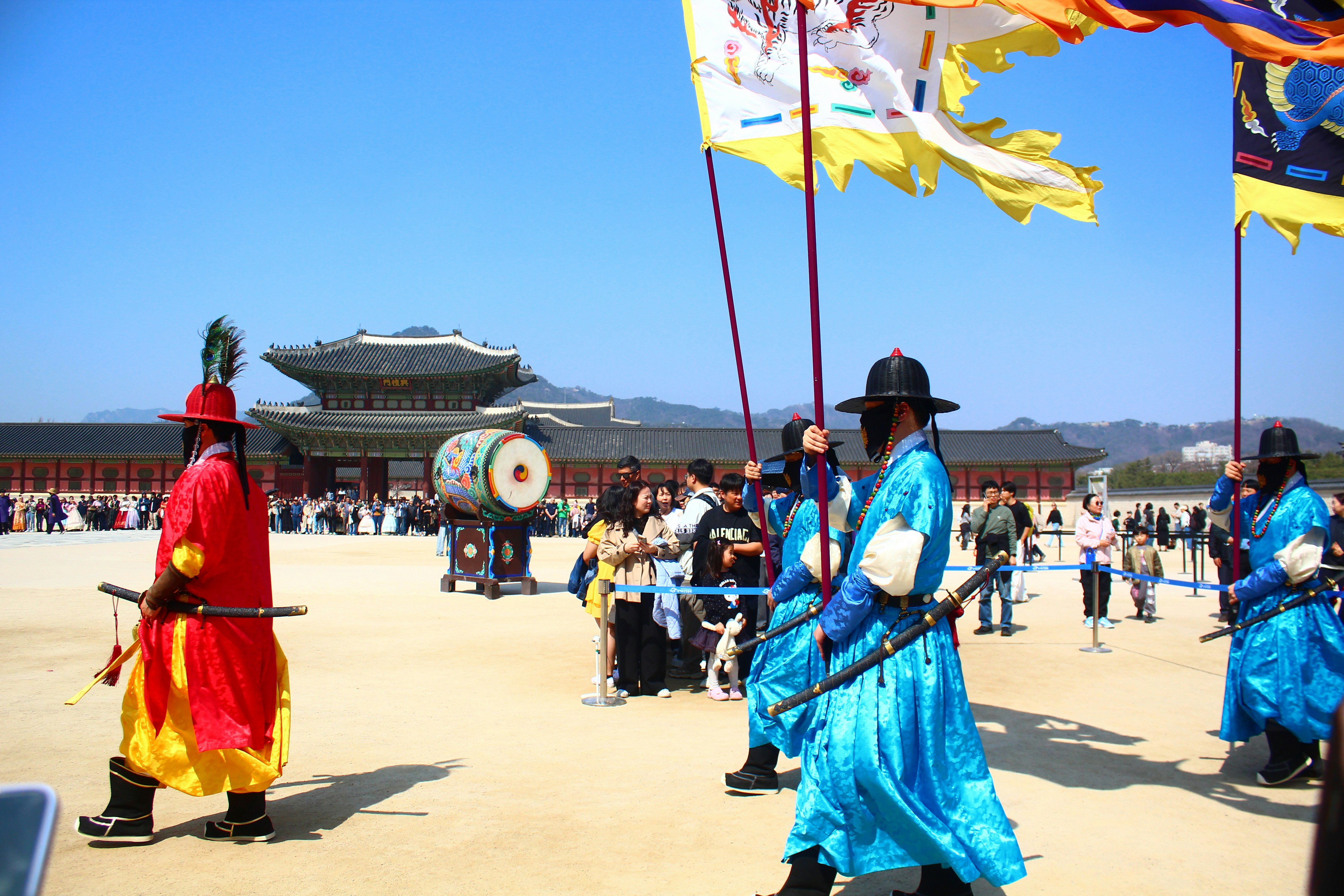 Blue Robes, Red Boots: A Flag-Bearing Parade Before the Palace