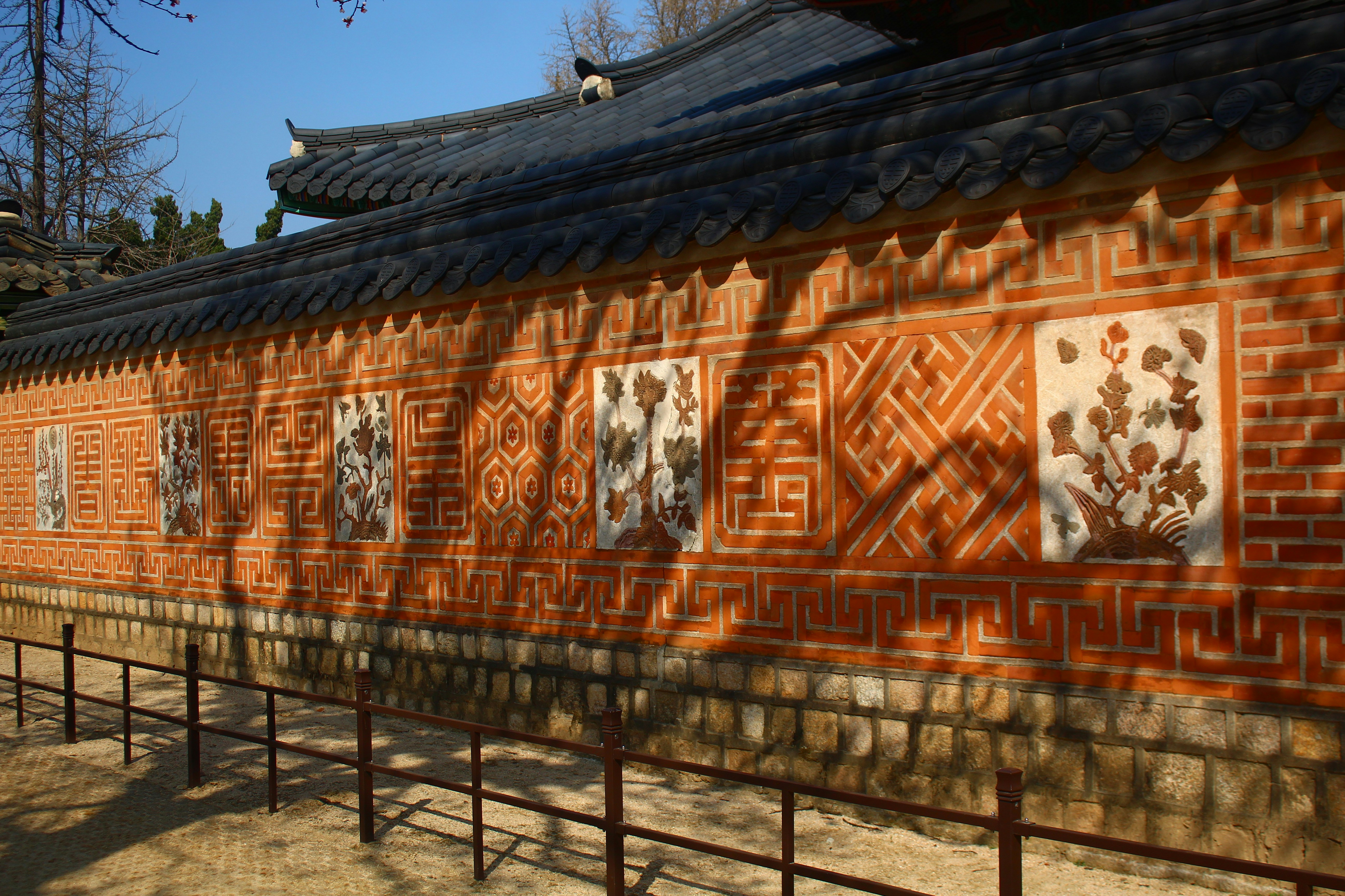 Sunlit Frieze: Painted Brickwork Along a Quiet Heritage Wall