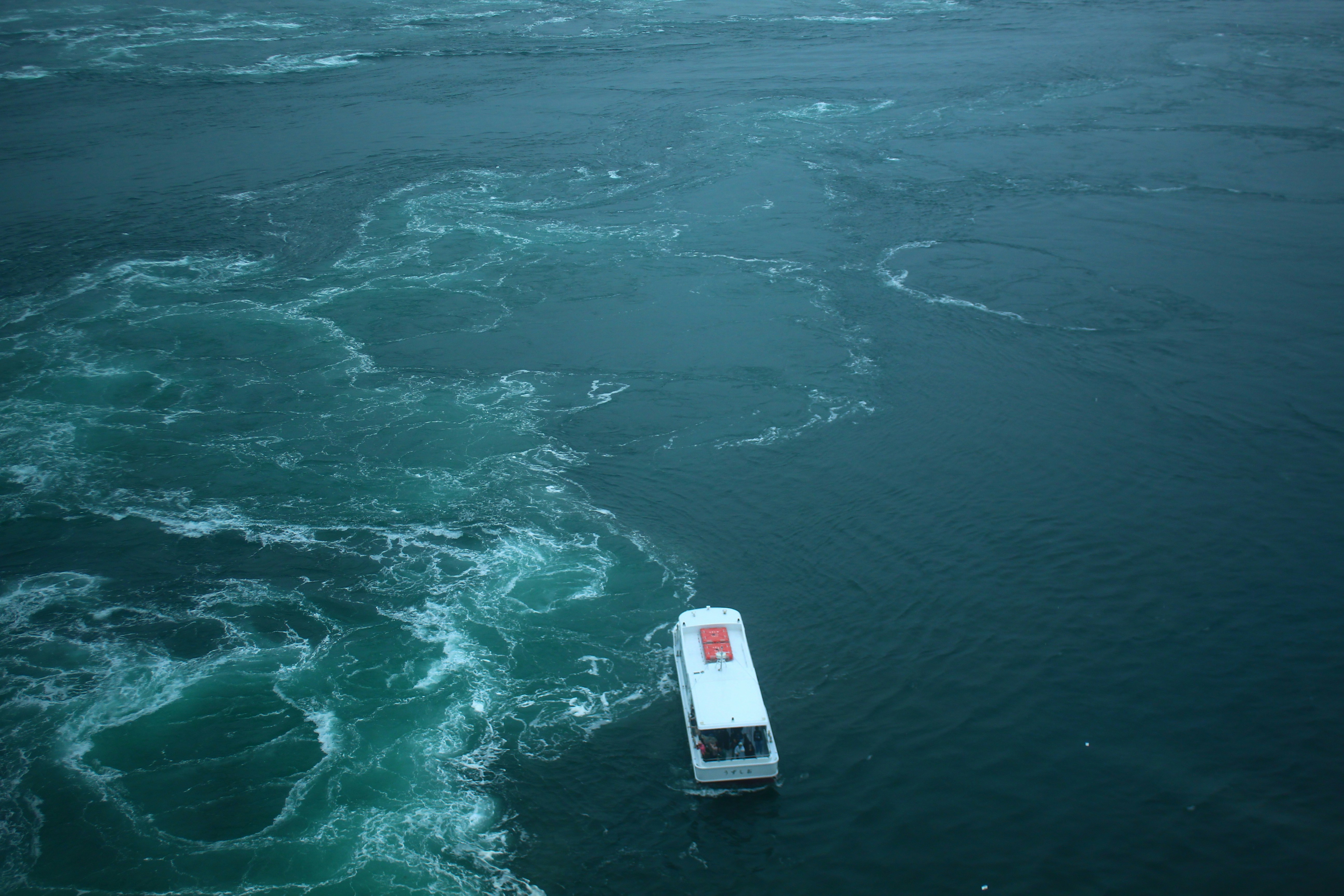 Mooring amid turquoise swirls: a lone boat on shifting sea