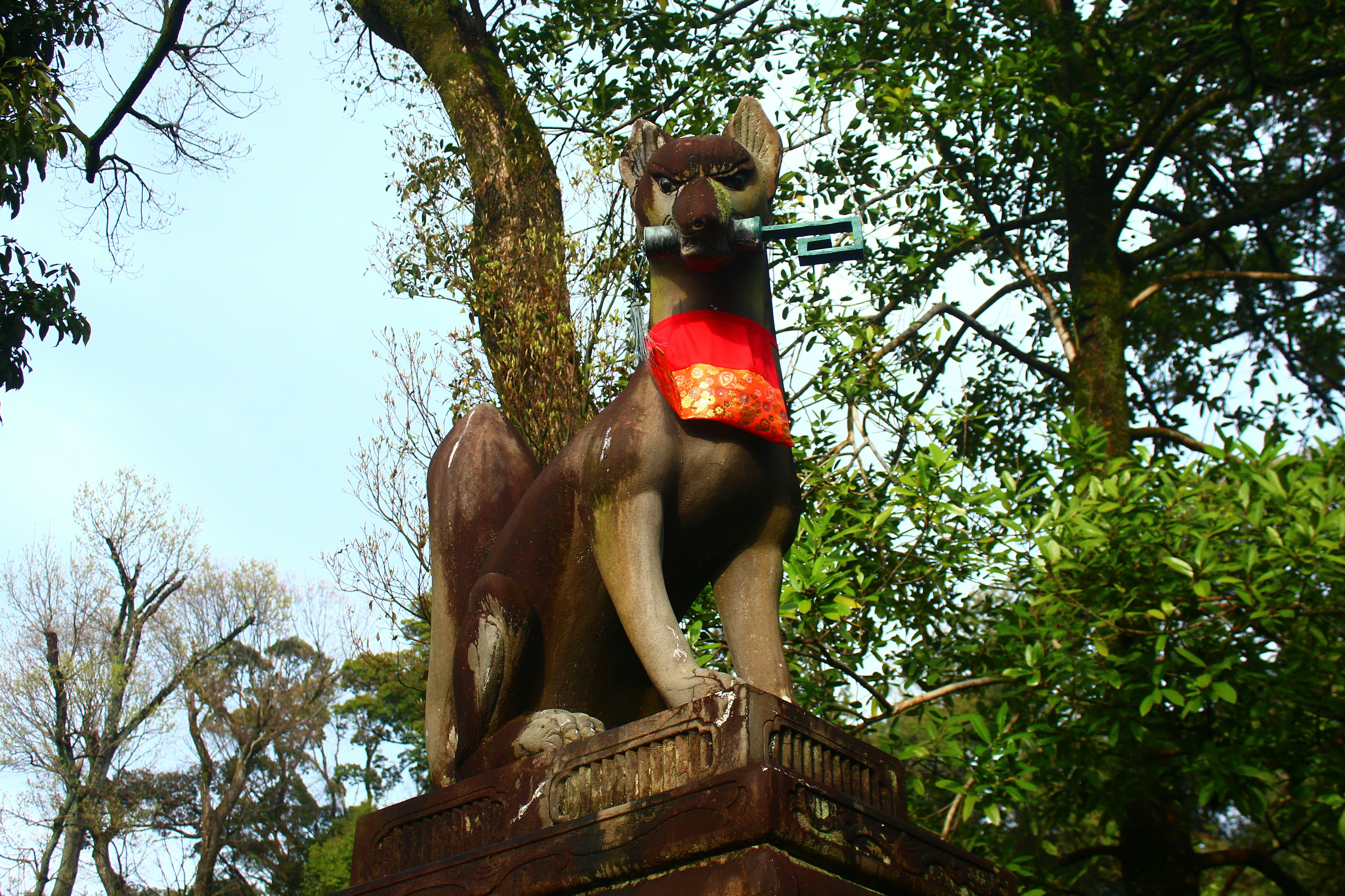 Fox Statue with Red Scarf Guarding an Ancient Pedestal