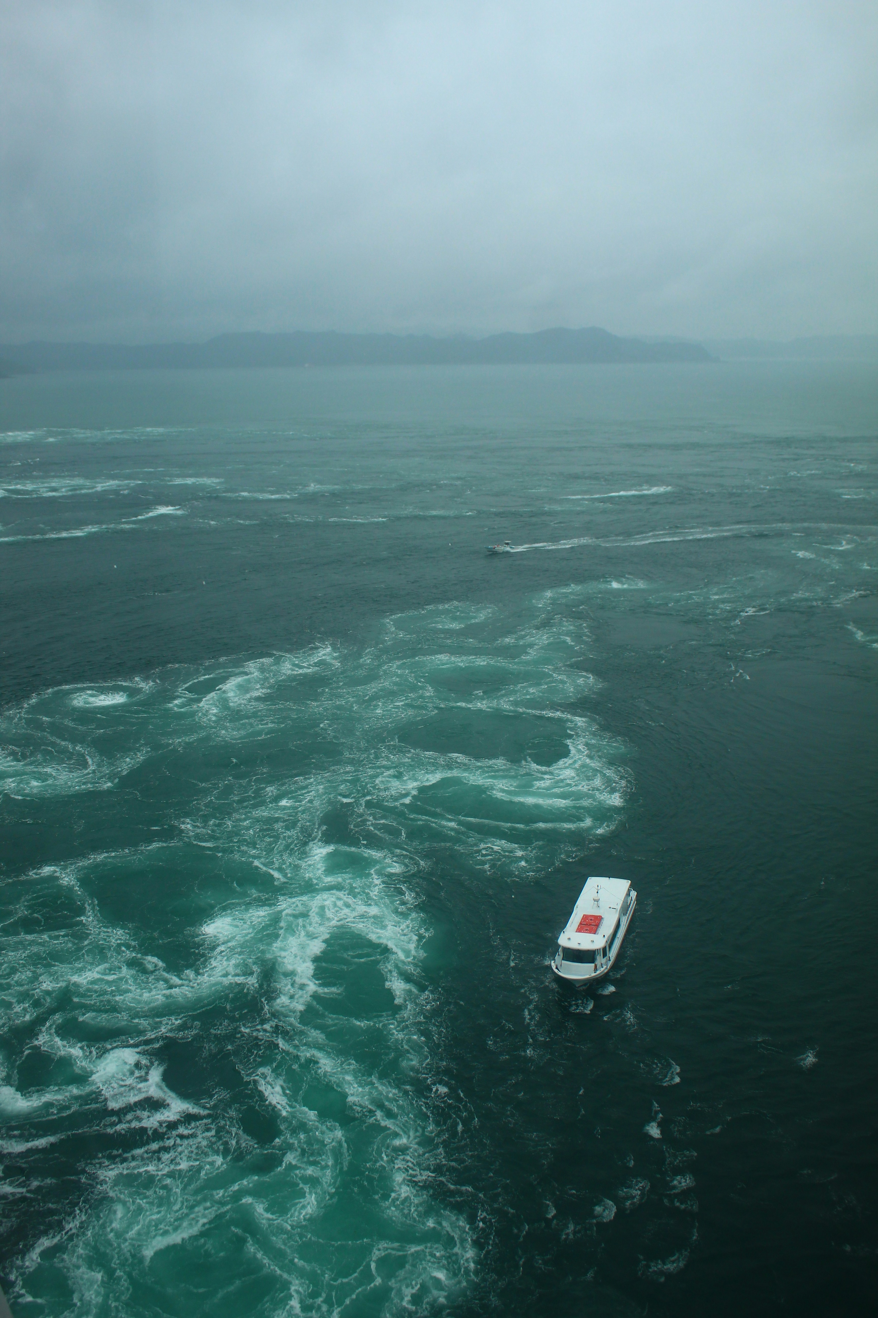 A lone vessel carves through turquoise swirls at sea