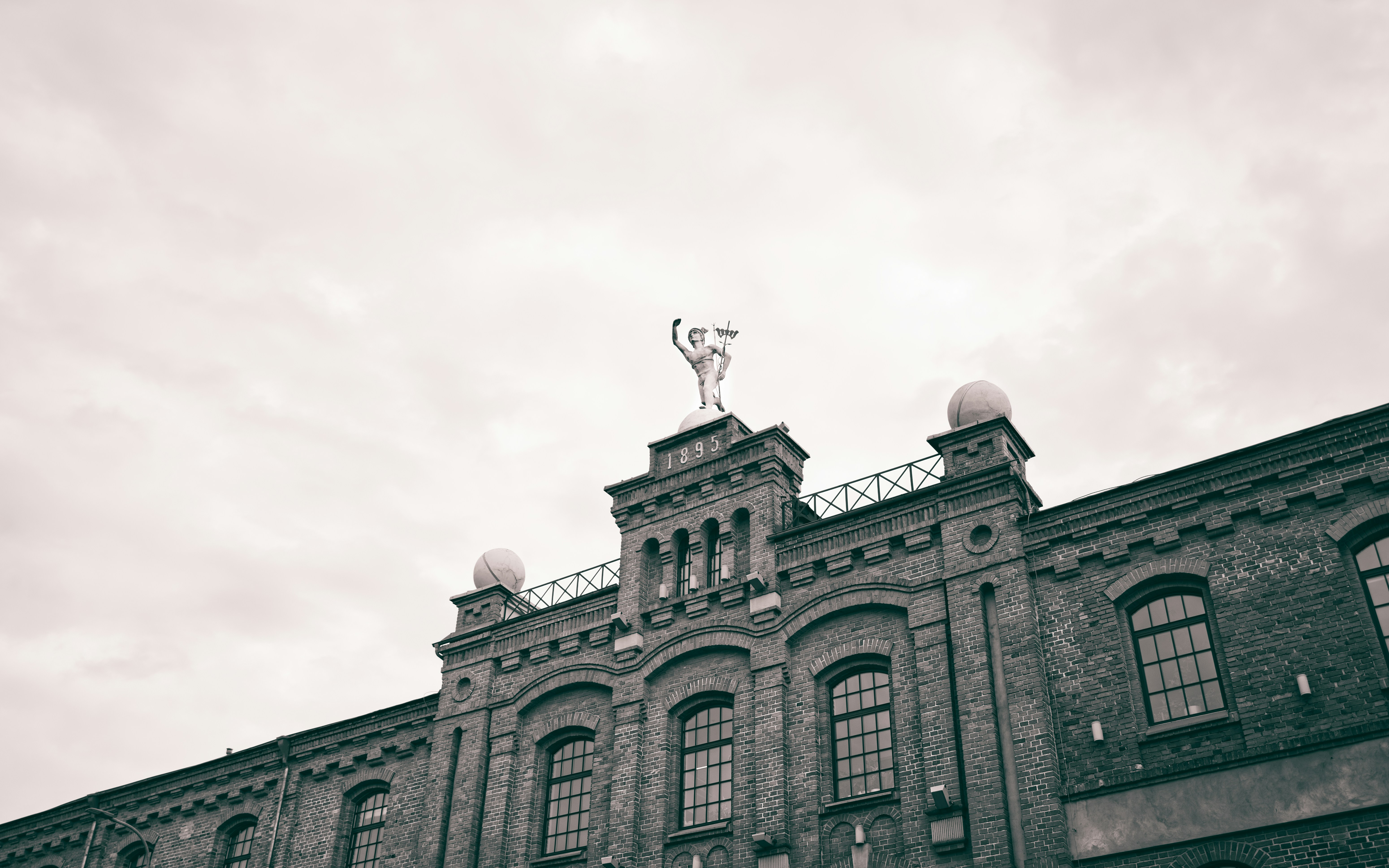 Statue Sentinel over Brick Facade: A Quiet Monument