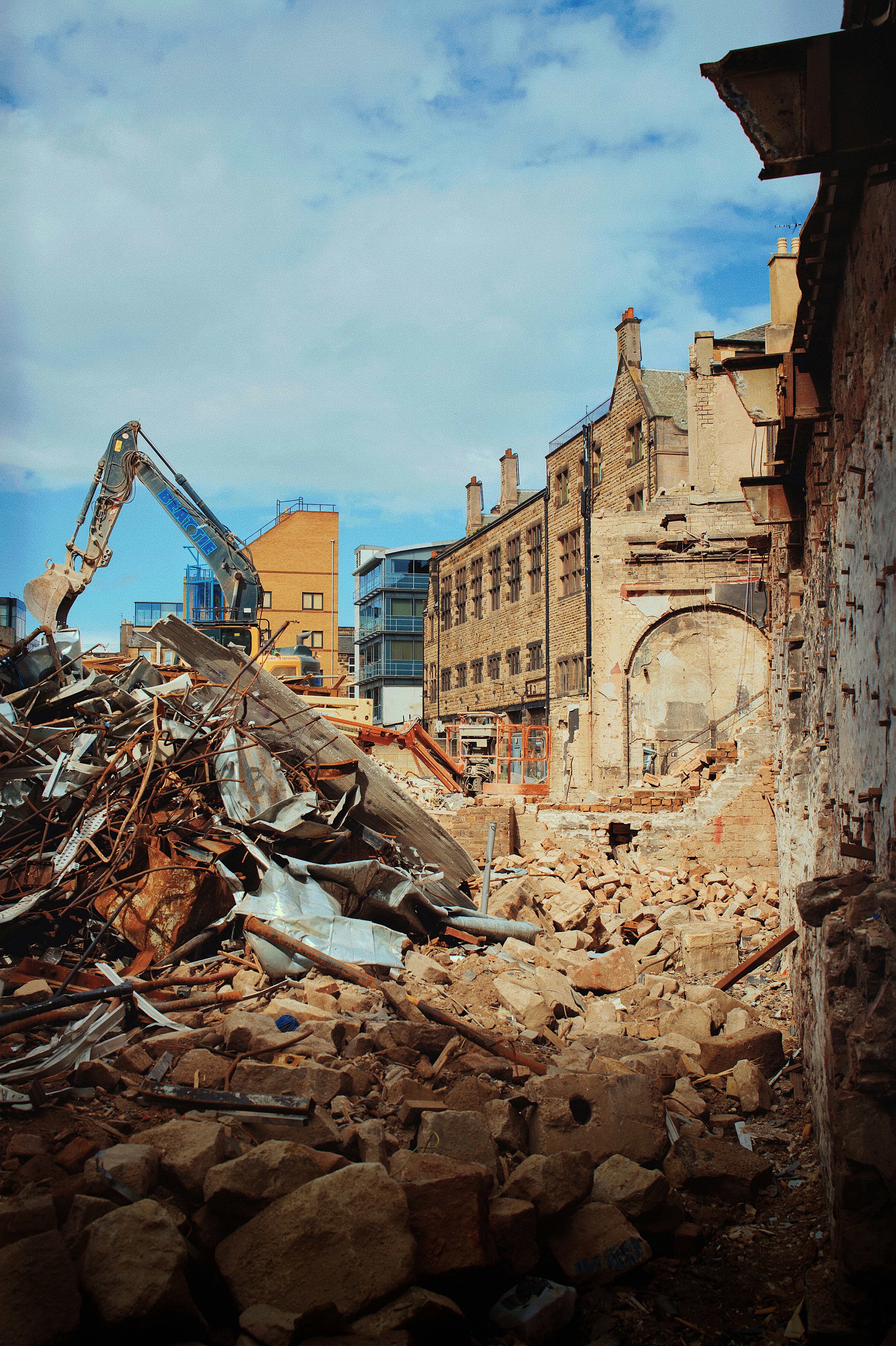 Rubble and machines beneath a partially rebuilt urban façade