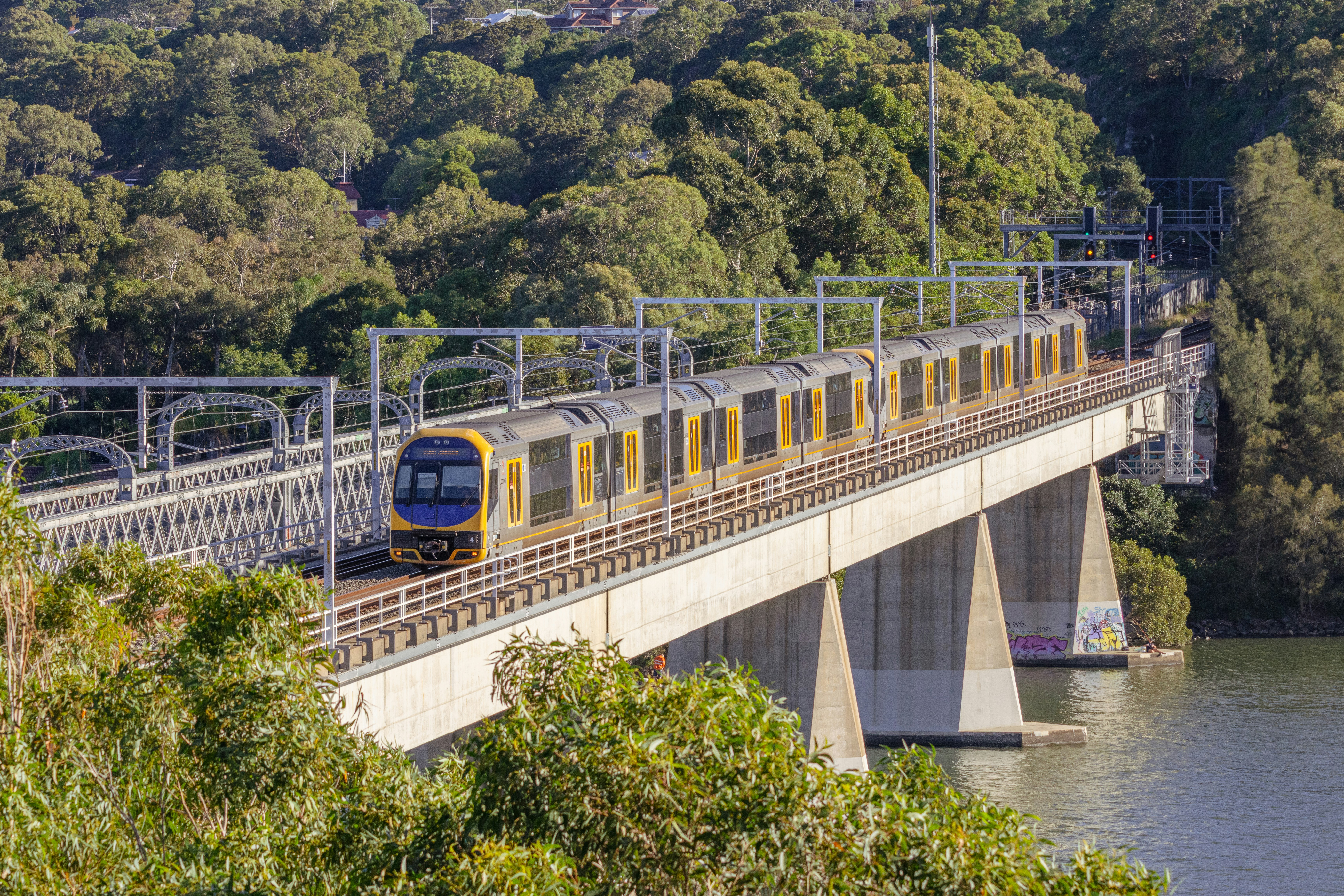Line of Light: A Yellow Commuter Crossing the River Bridge