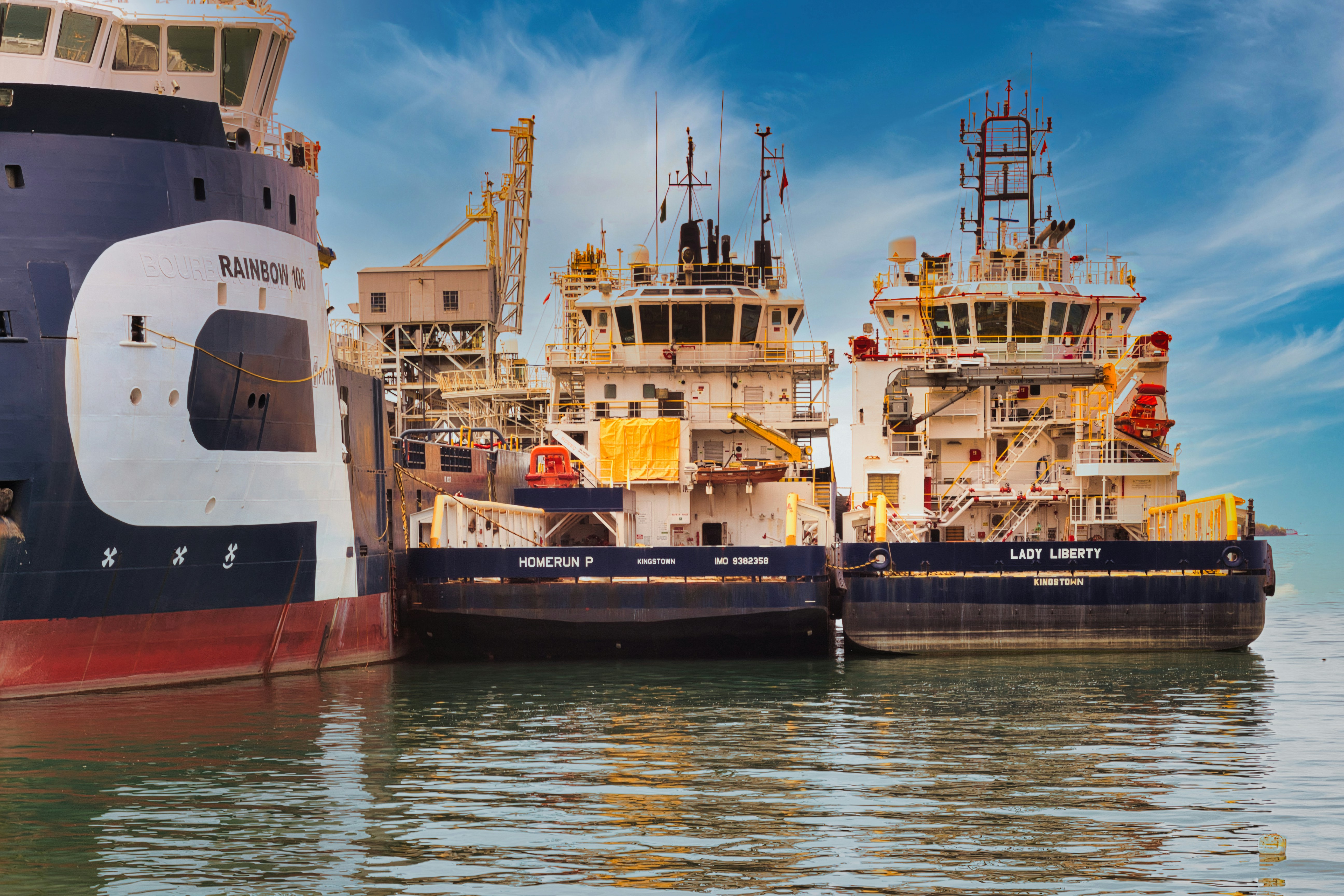 Docked Giants: Three Trawlers Resting at the Sunlit Quay