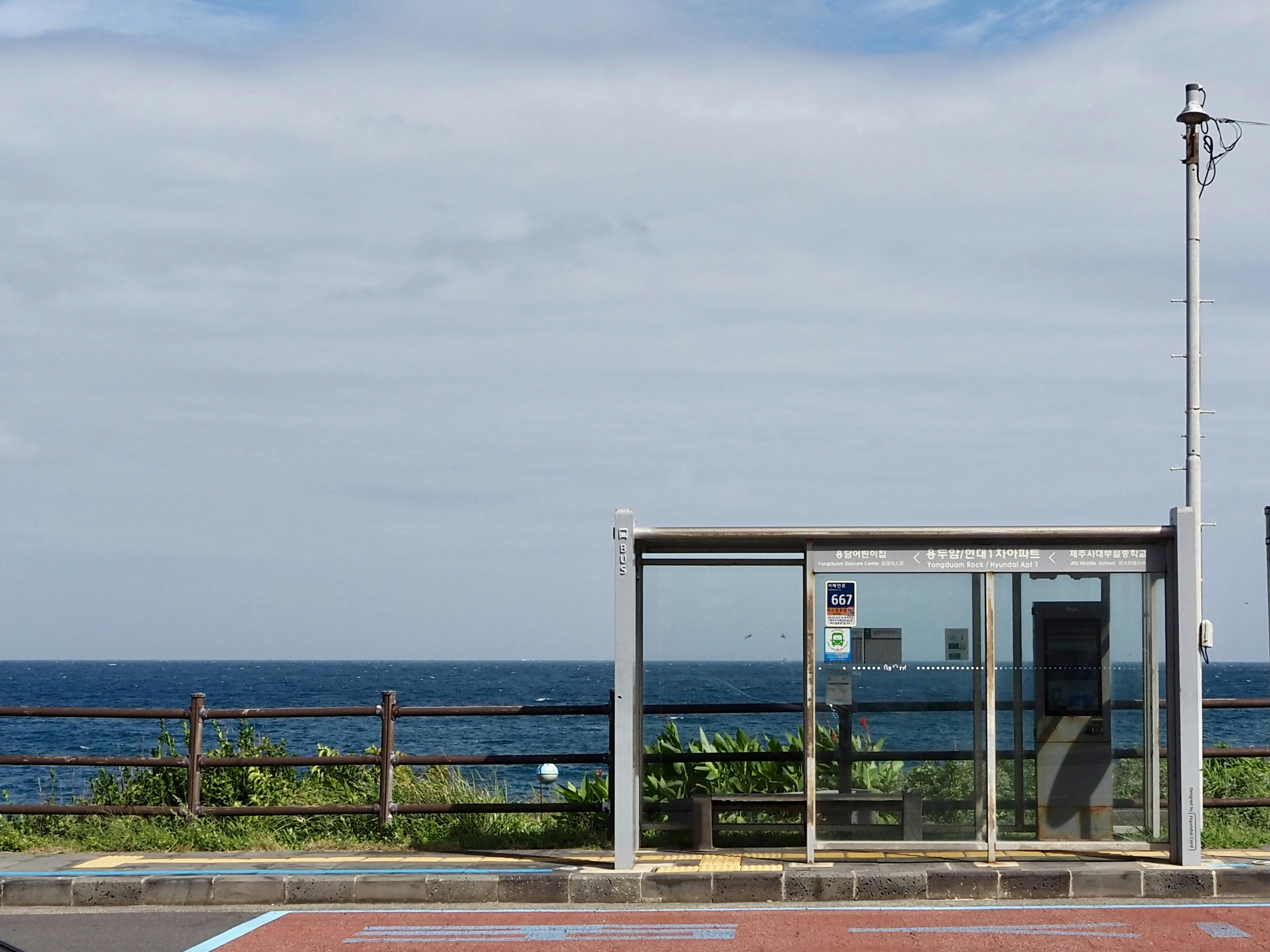Bus Stop by the Sea: Glass, Railings, and Ocean Horizon