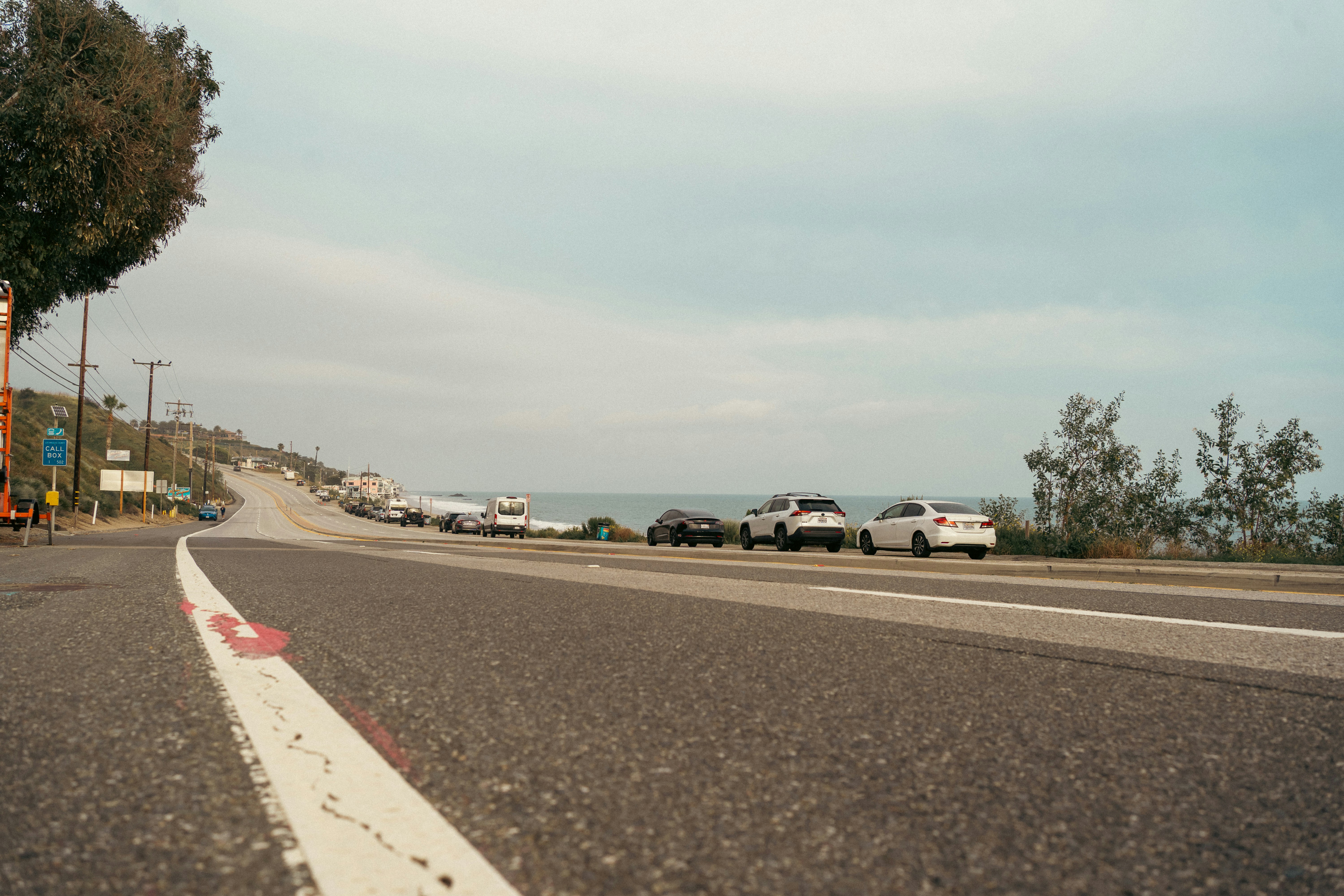 Low Tide at the Coastal Road: Cars, Curbs, and Calm Skies