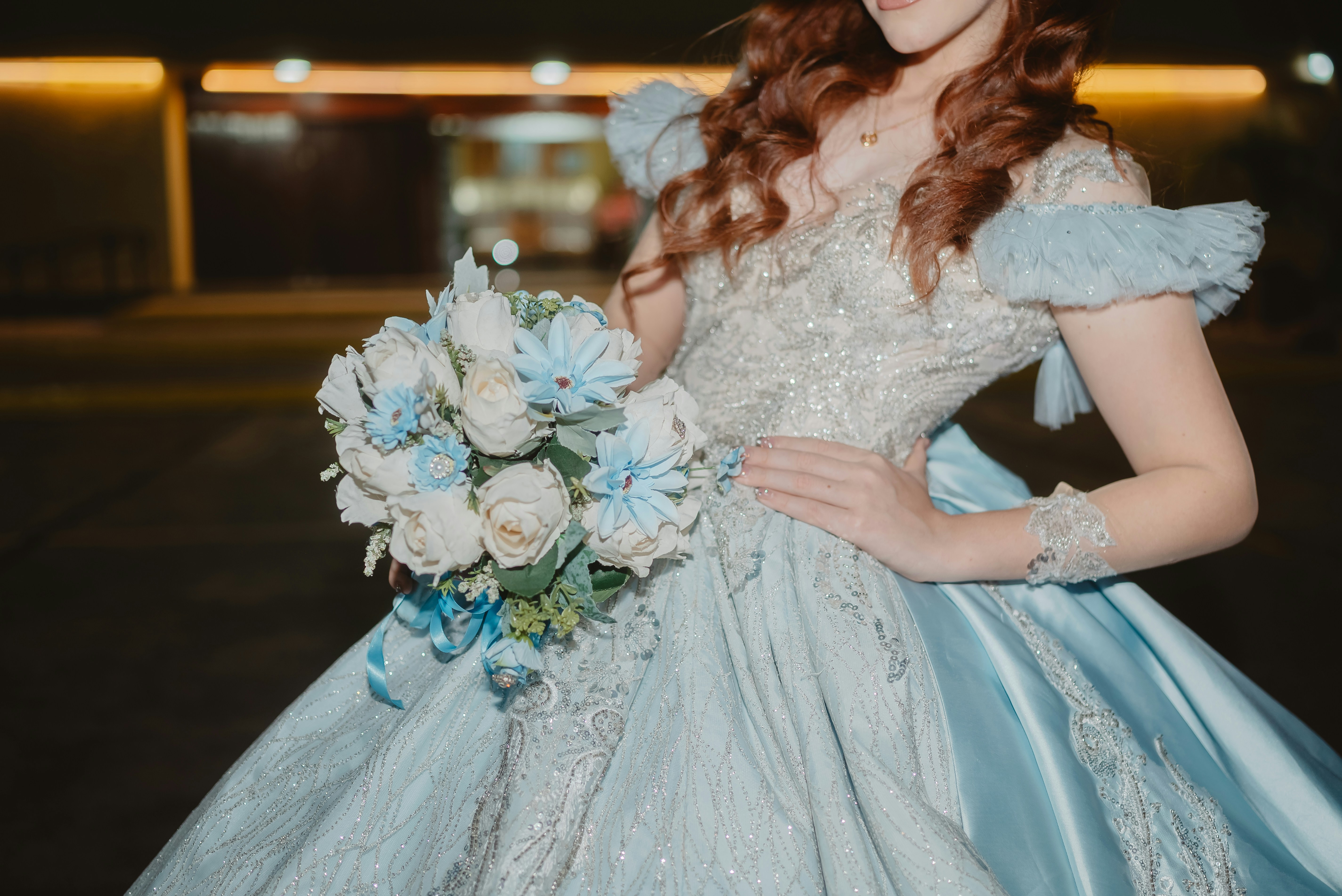 Blue-tinted bridal gown and bouquet luminous under evening lights