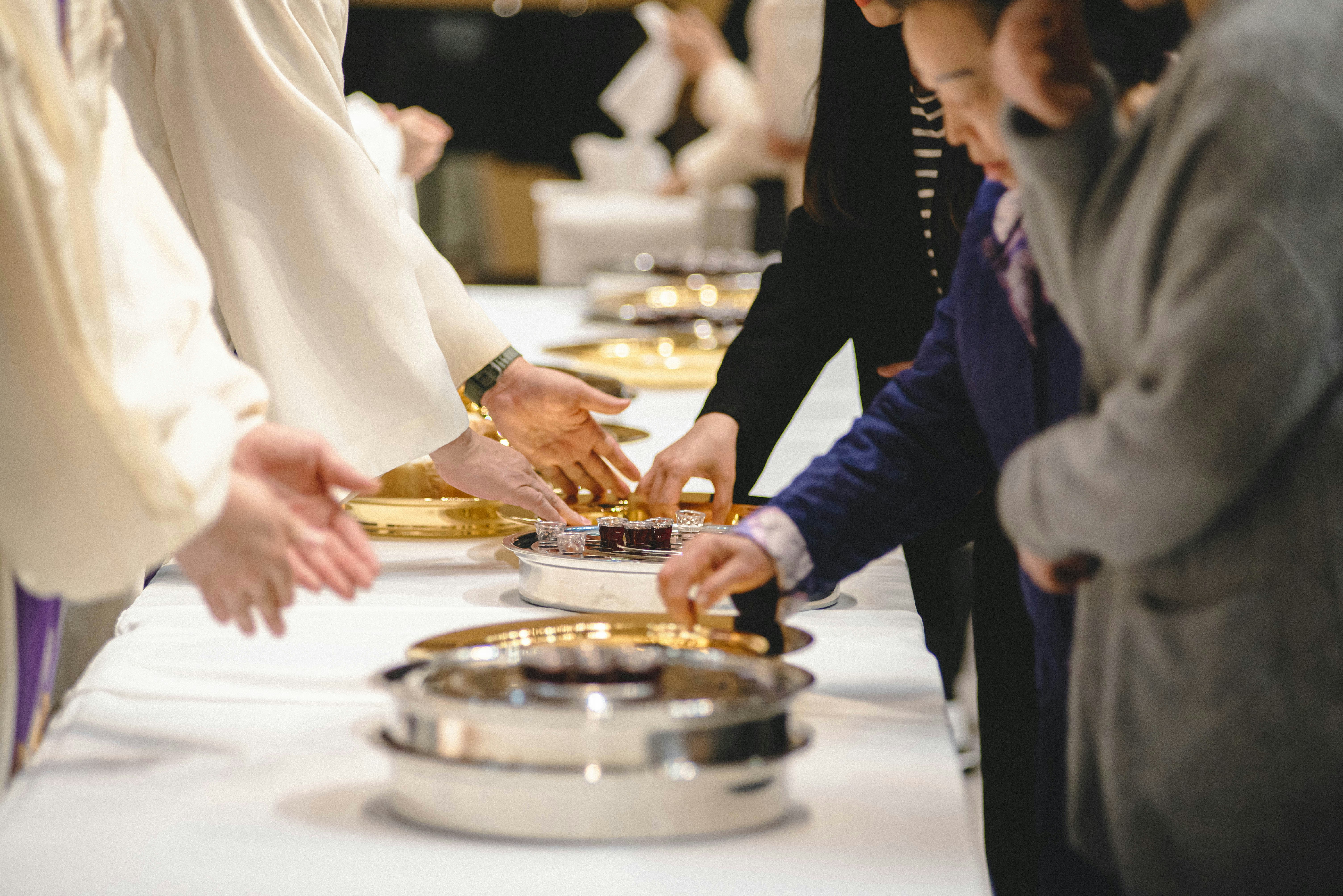 Served in Silver: A Row of Hands and Chafing Dishes at a Buffet