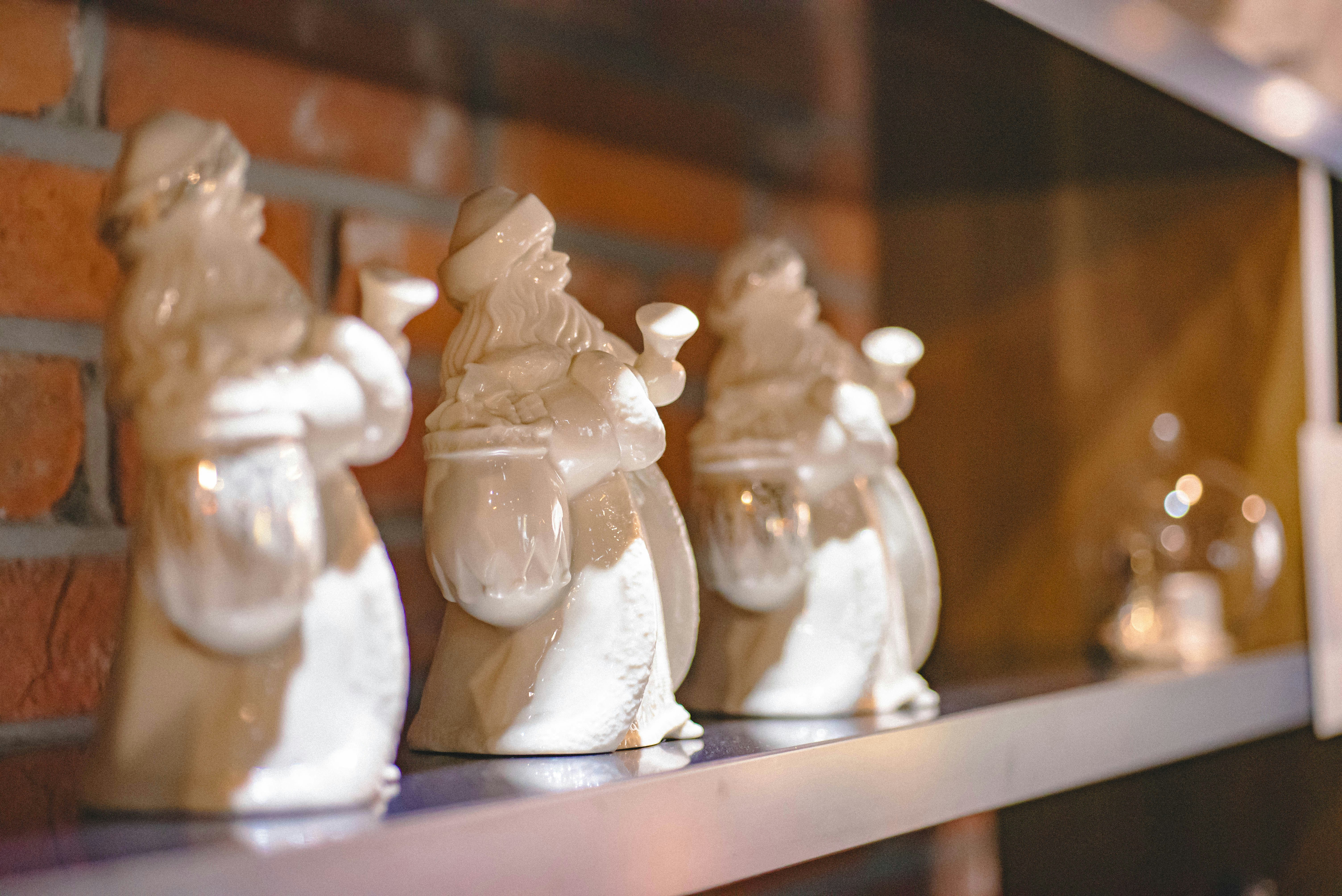 Row of Ivory Figurines on a Glass Shelf by a Brick Wall