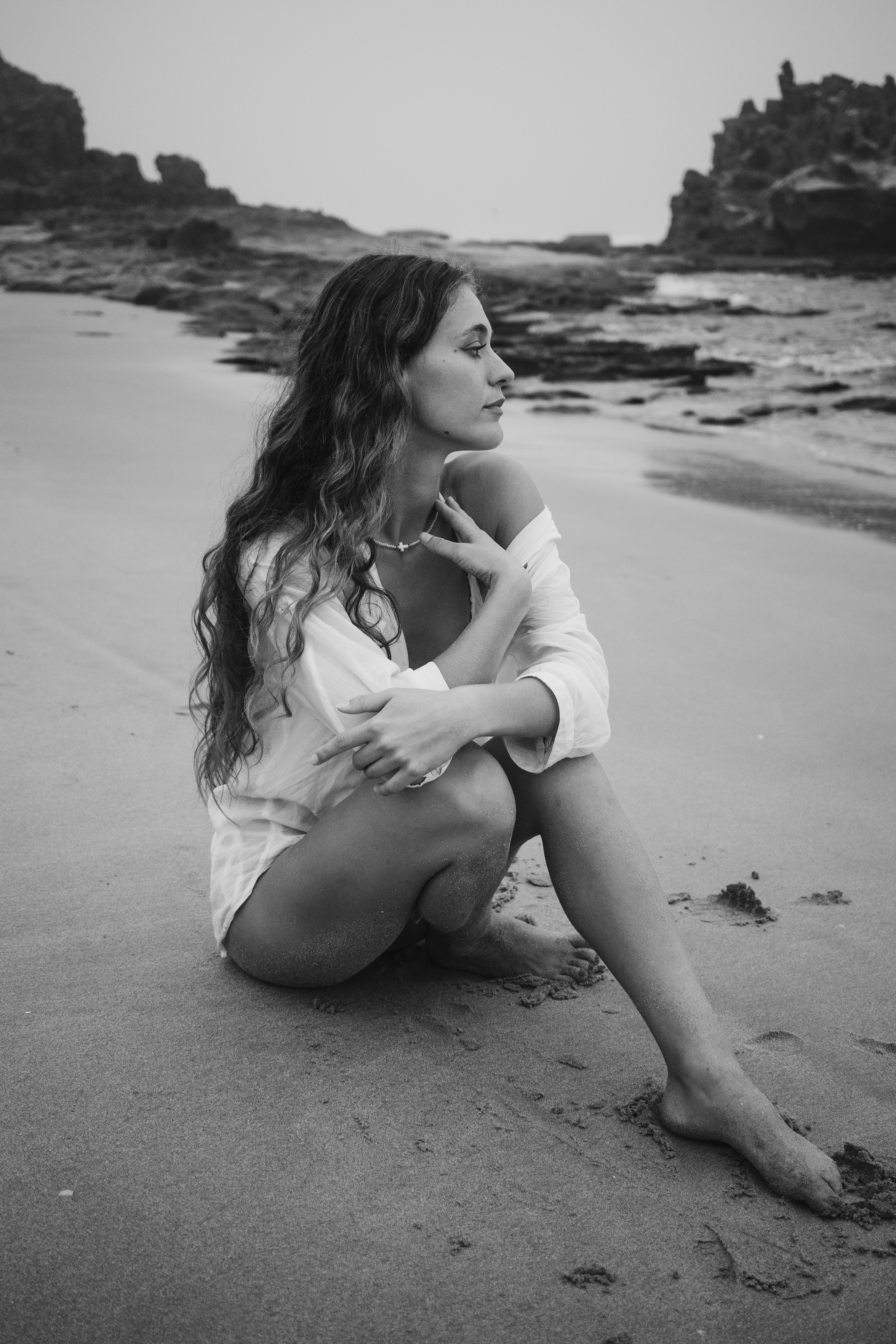 Coastal Quiet: A Seated Portrait on Shoreline Noir