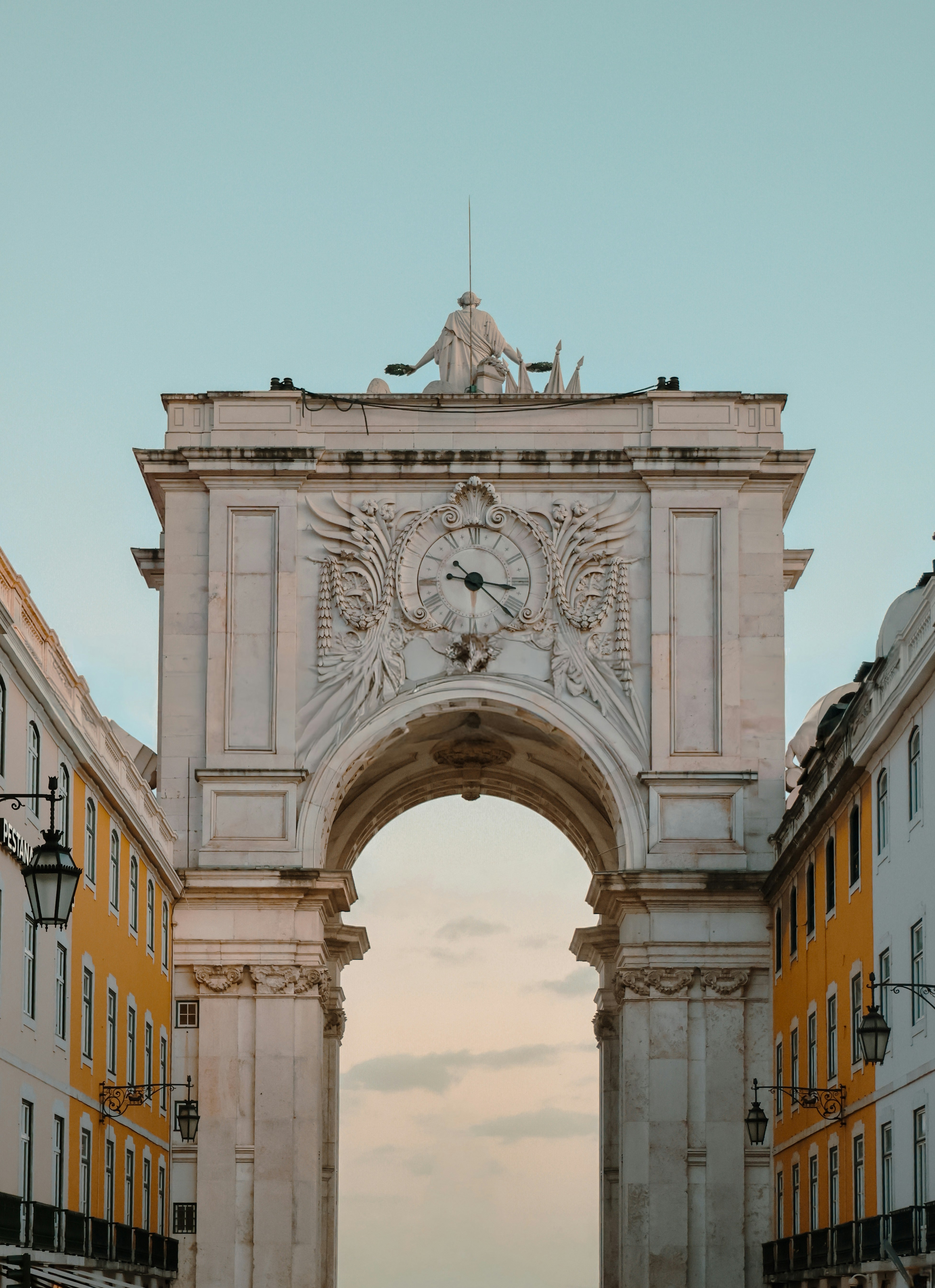Arched Gate of Dawn: A Neoclassical Monument Framed by Colorful Street Facades