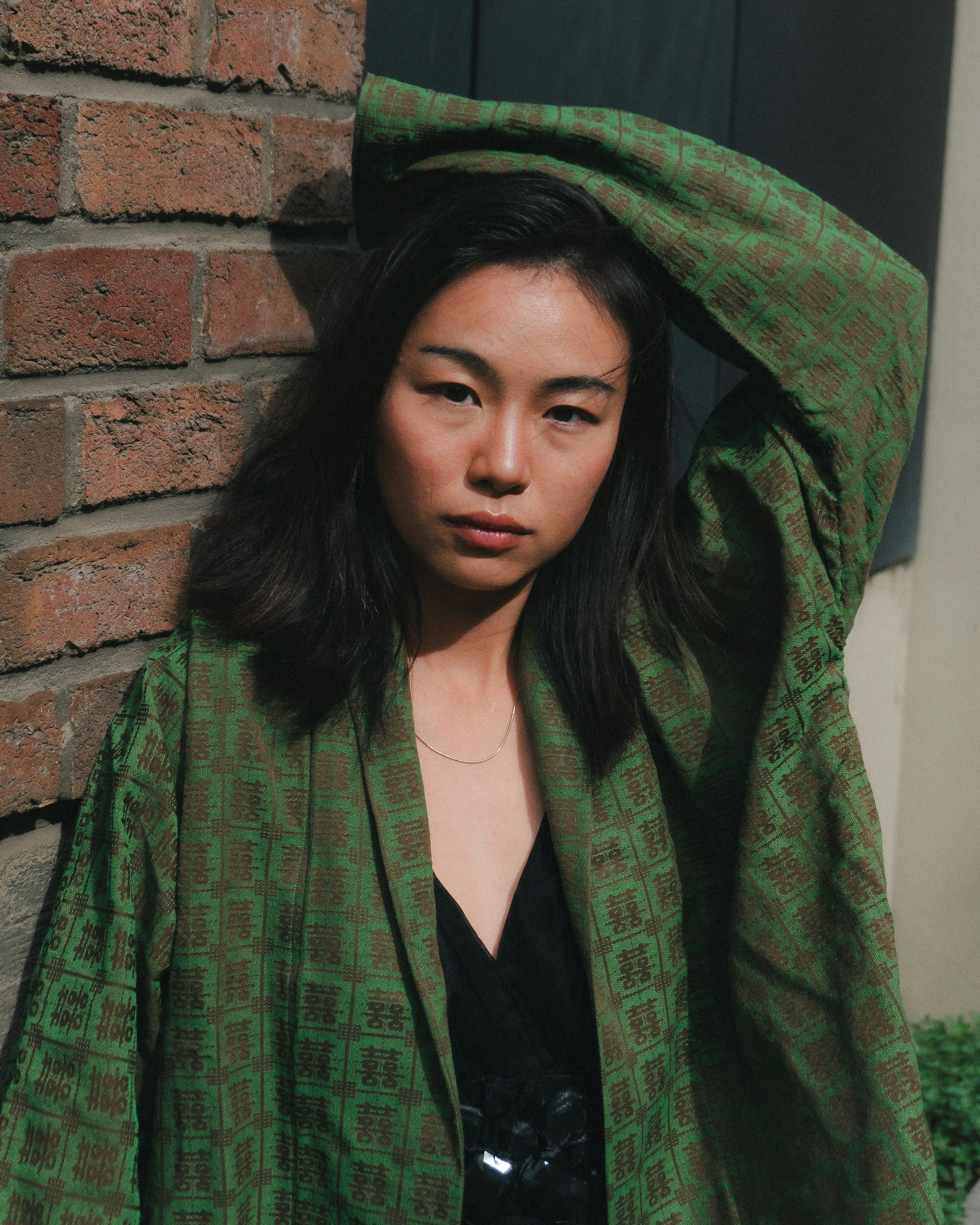 Green Draped Quietude: A Portrait against Brick