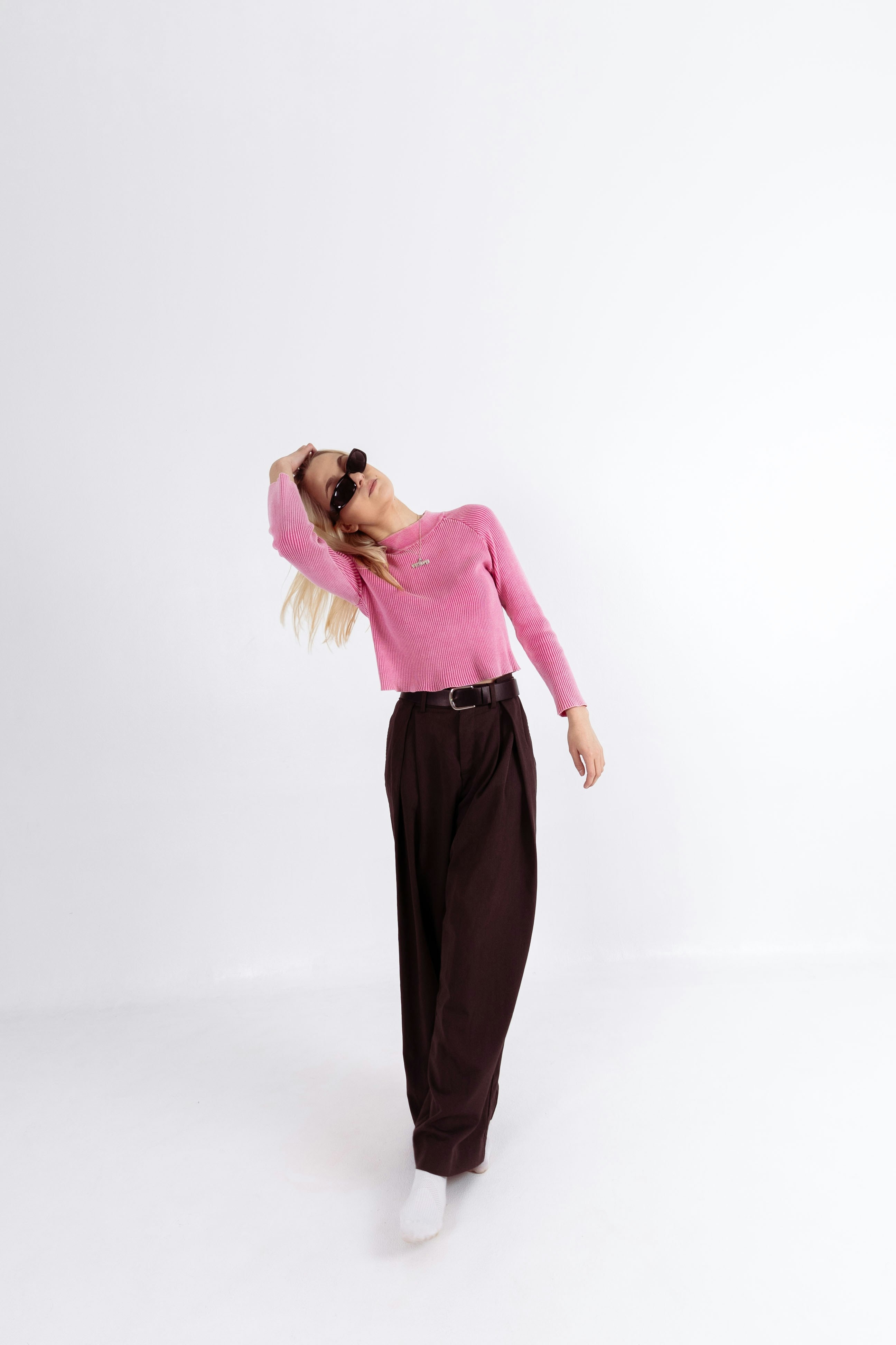 Pink Sweater, Wide Trousers: A Playful Tilt in a White Studio
