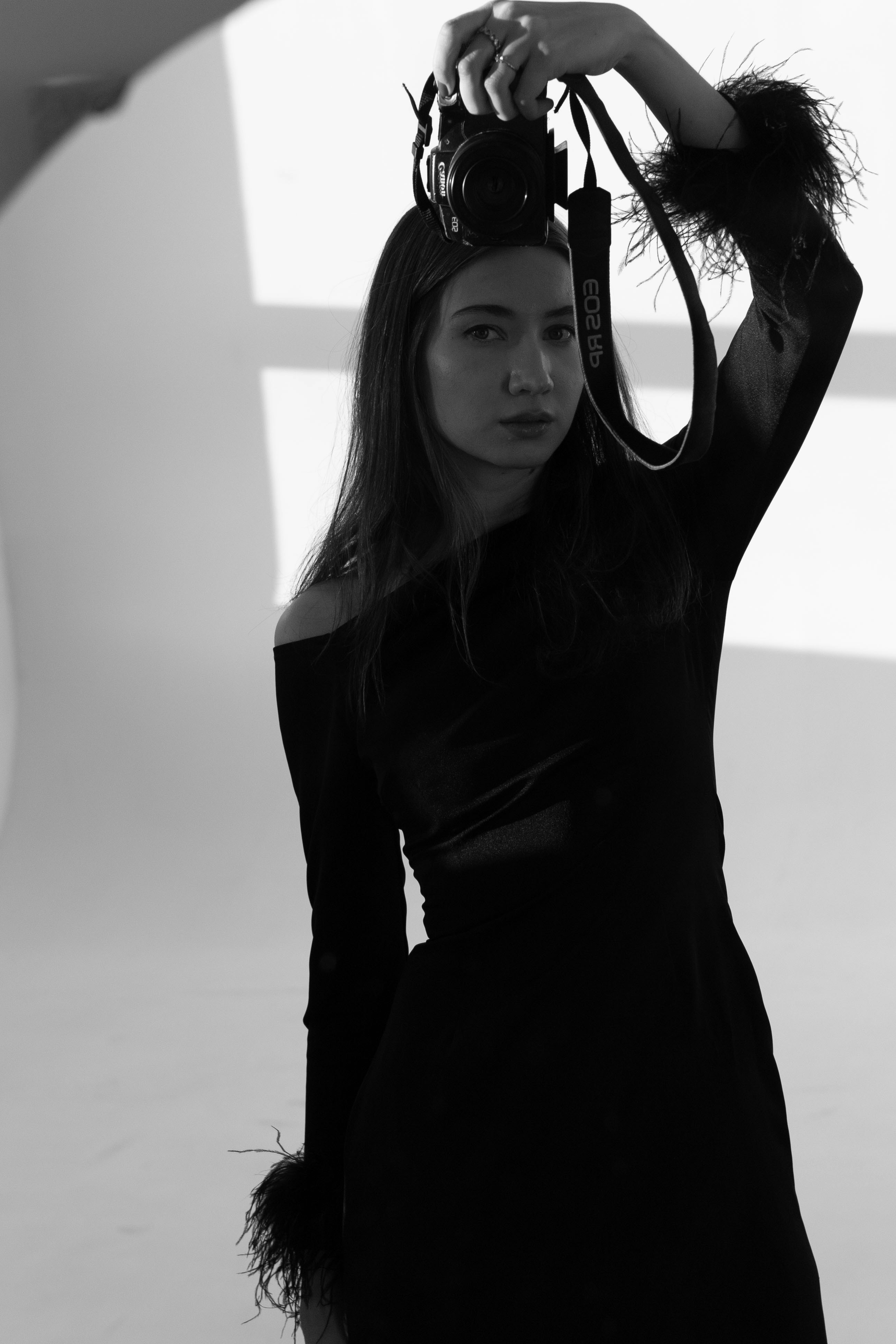 Self-portrait in monochrome: a poised photographer lifts the camera above her head