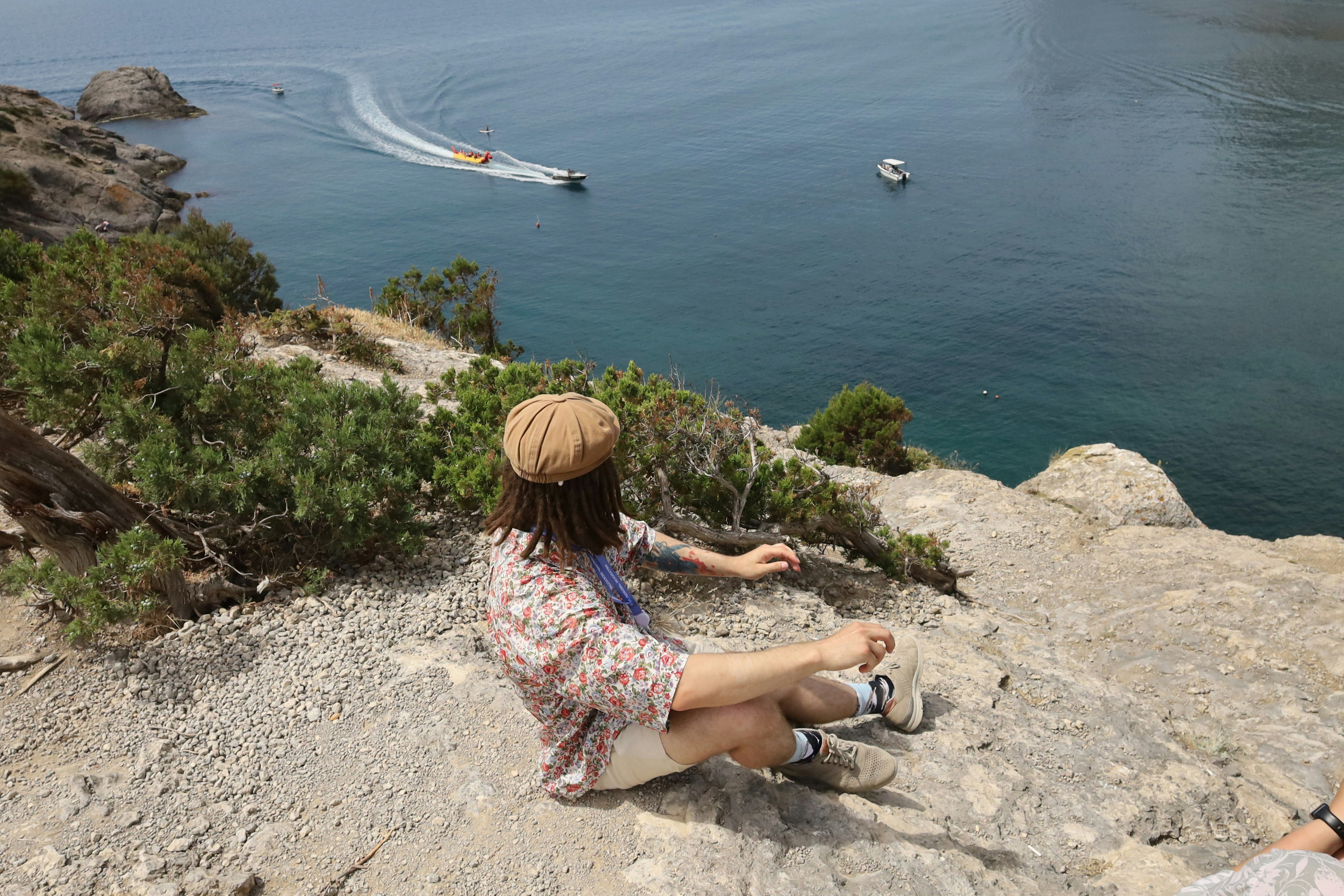 A cliffside pause: sunlit traveler overlooking the tranquil harbor