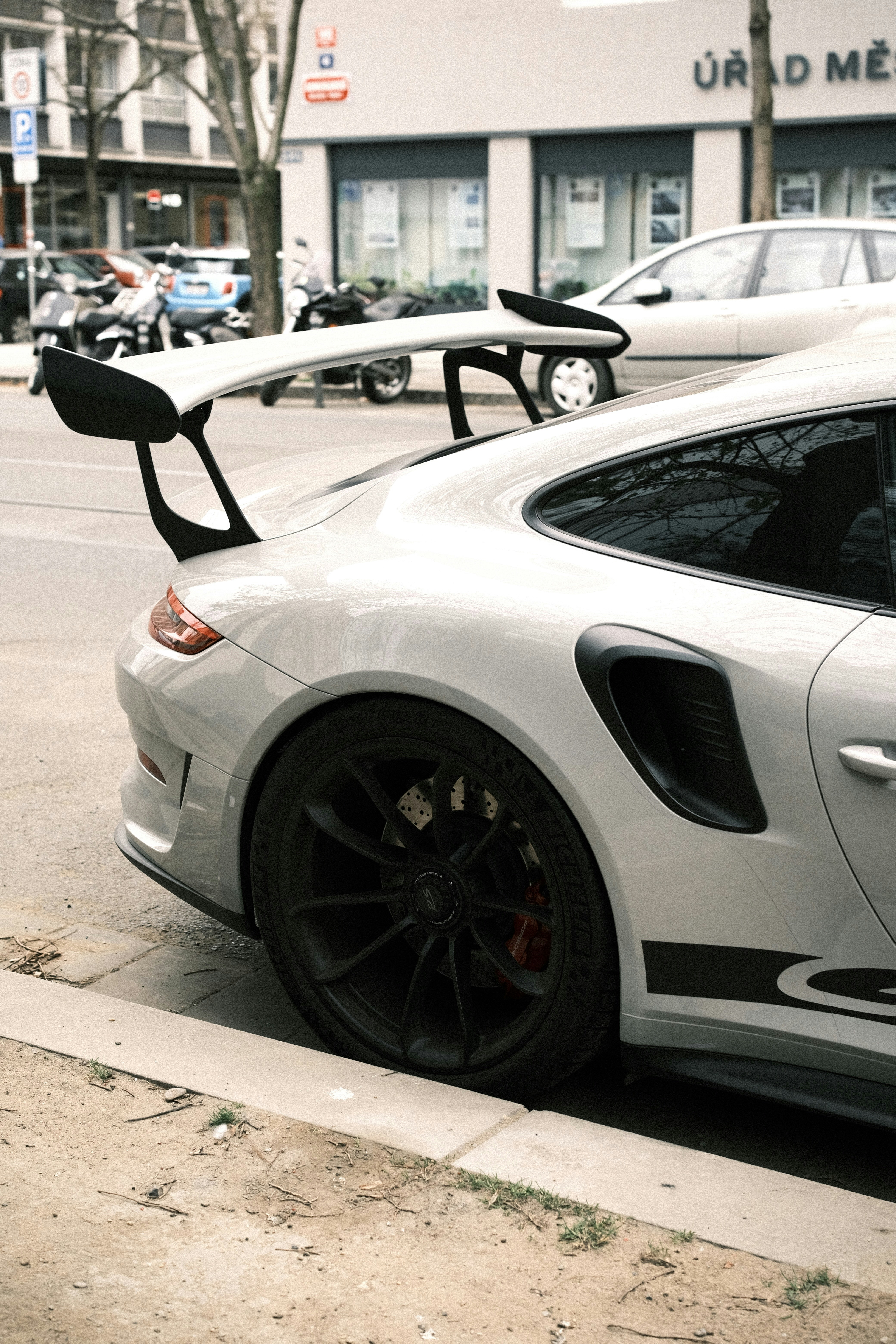 Rear Wing Symphony: A Silver Porsche Slices Streetlight Quiet
