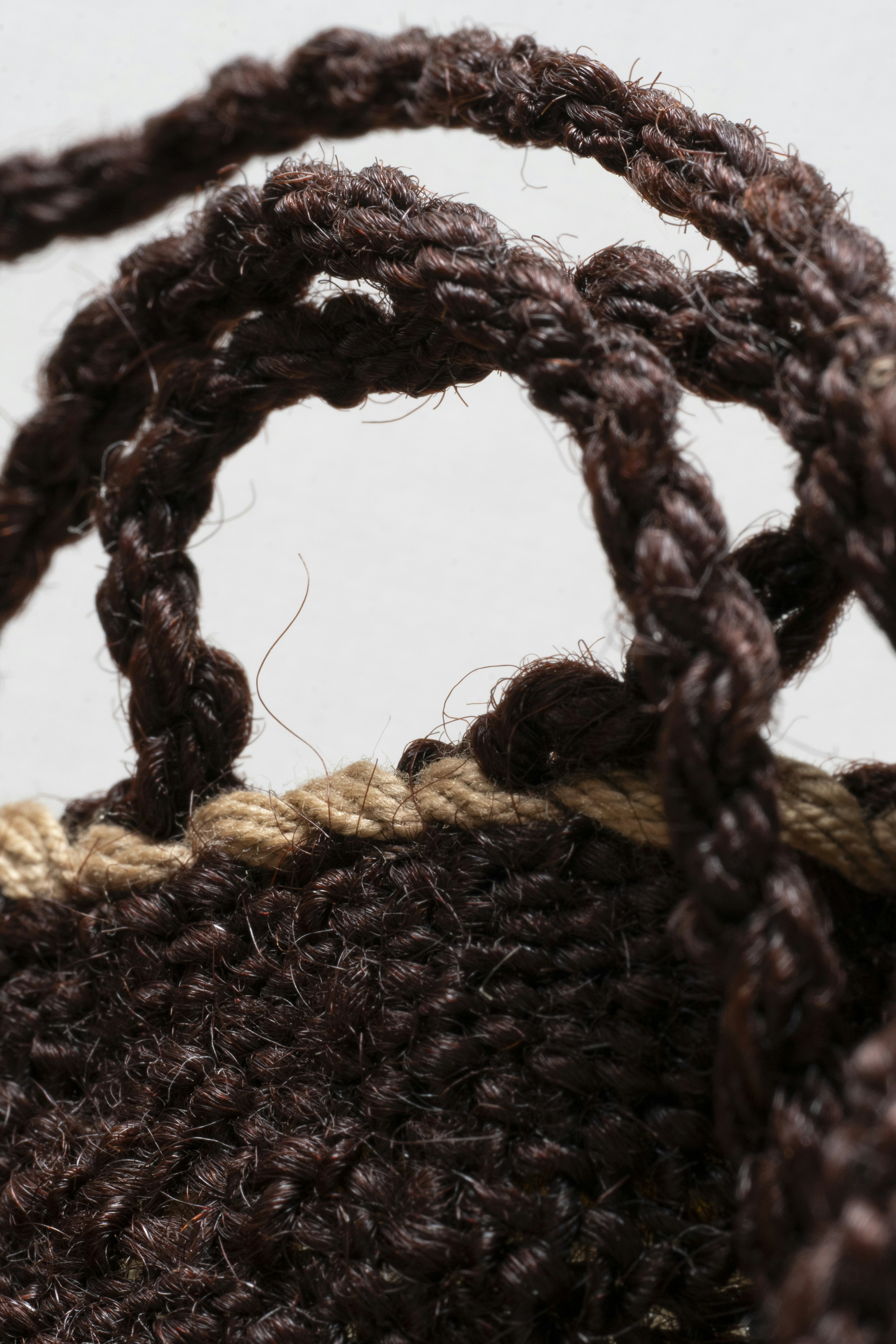 Braided Silence: Close‑up of Twisted Rope Handles on a Textured Straw Bag