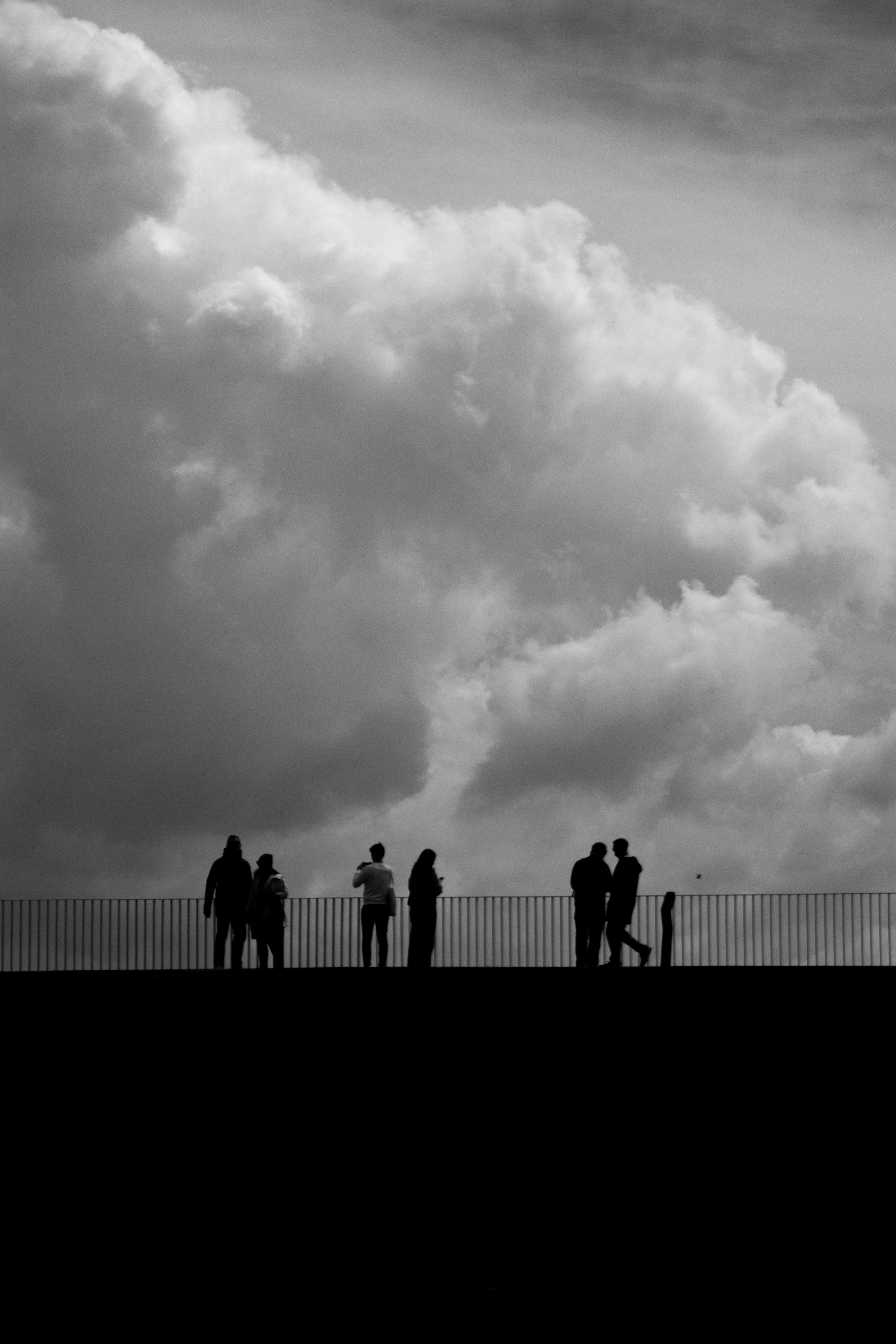 Silhouetted on the Edge: A Line of Figures Beneath a Risen Cloud