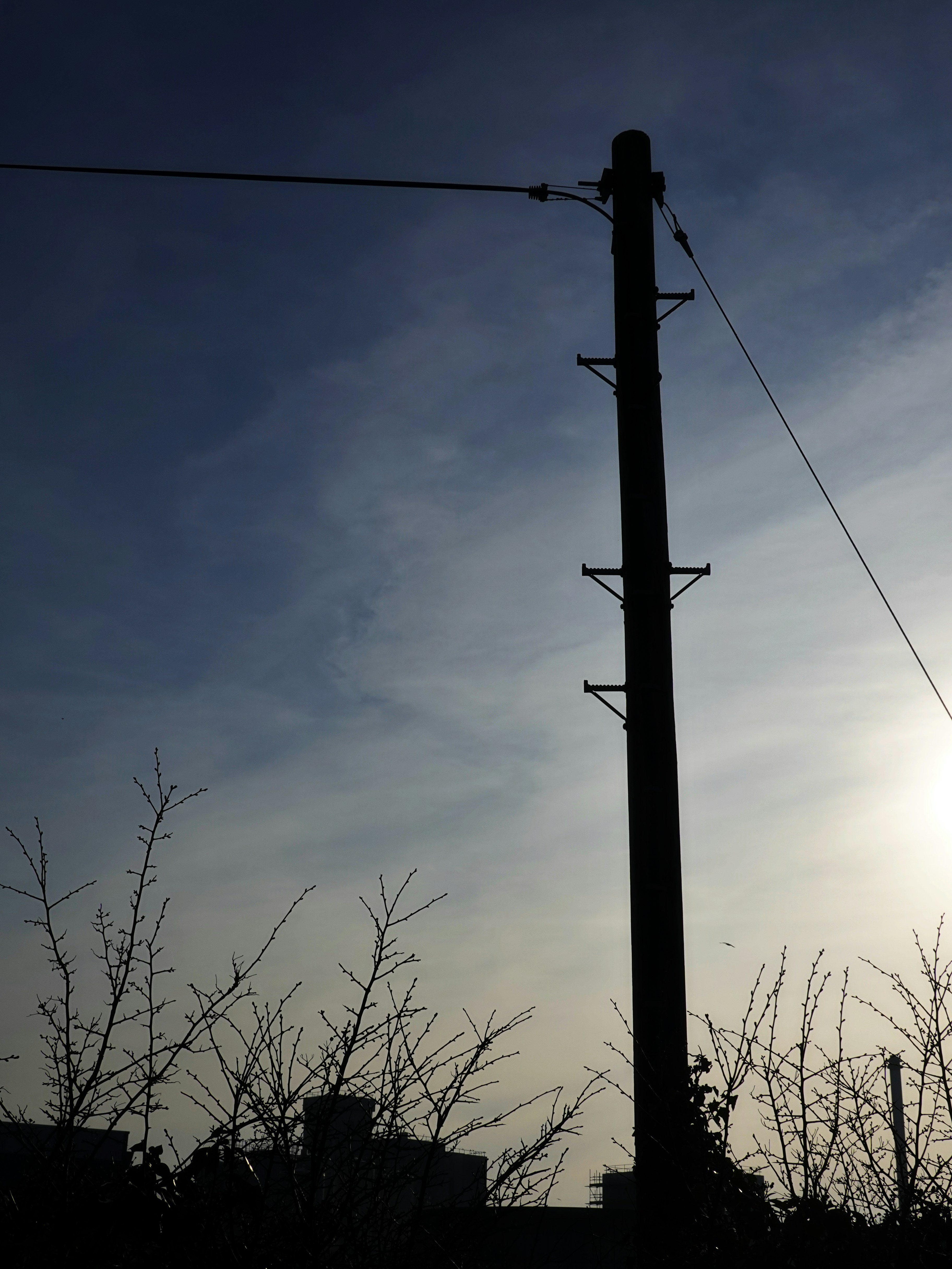 Silhouette of a Utility Mast Against a Pale Sky at Sunset