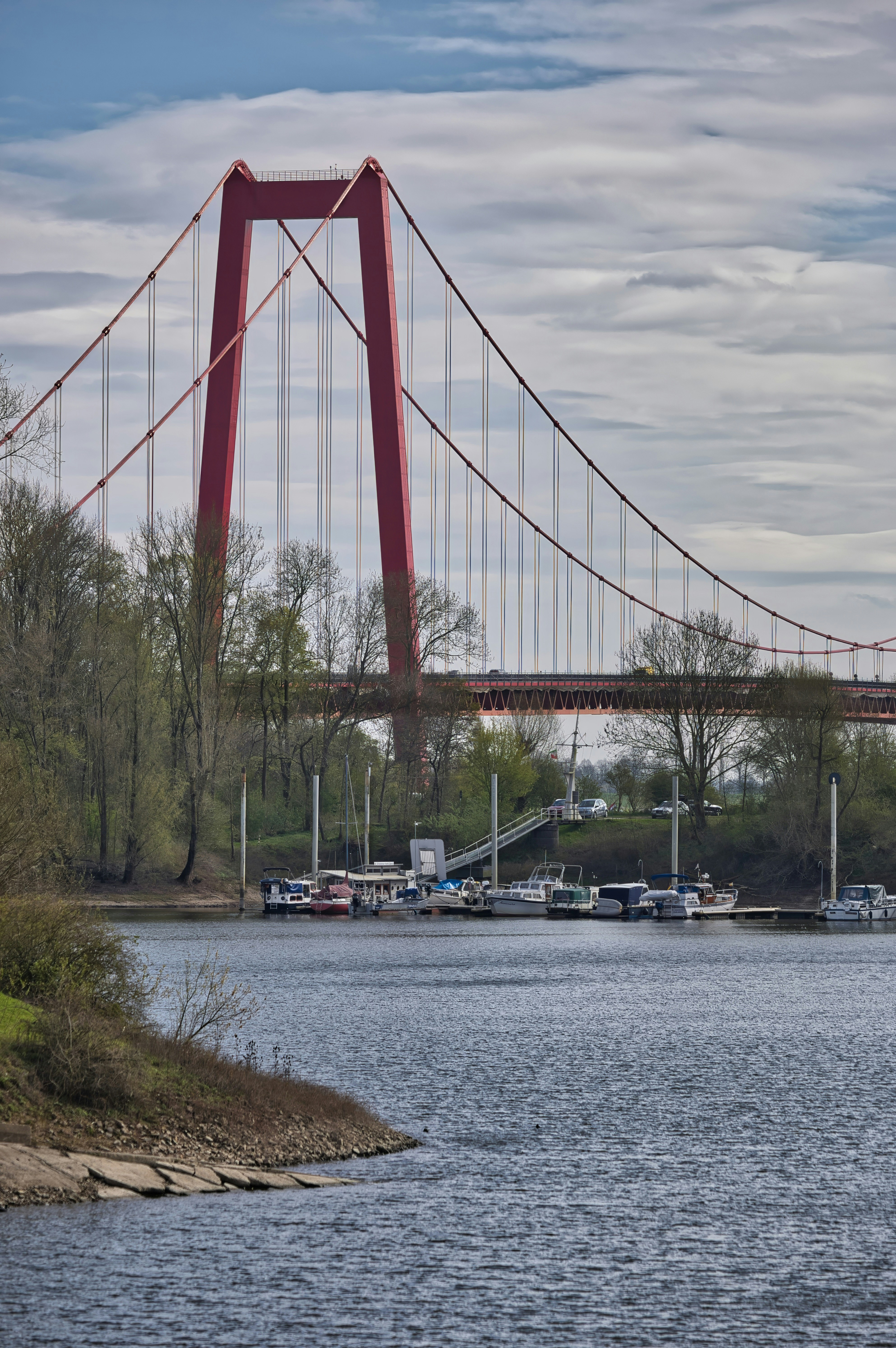 Red arch over calm waters: a riverside scene with a suspension bridge