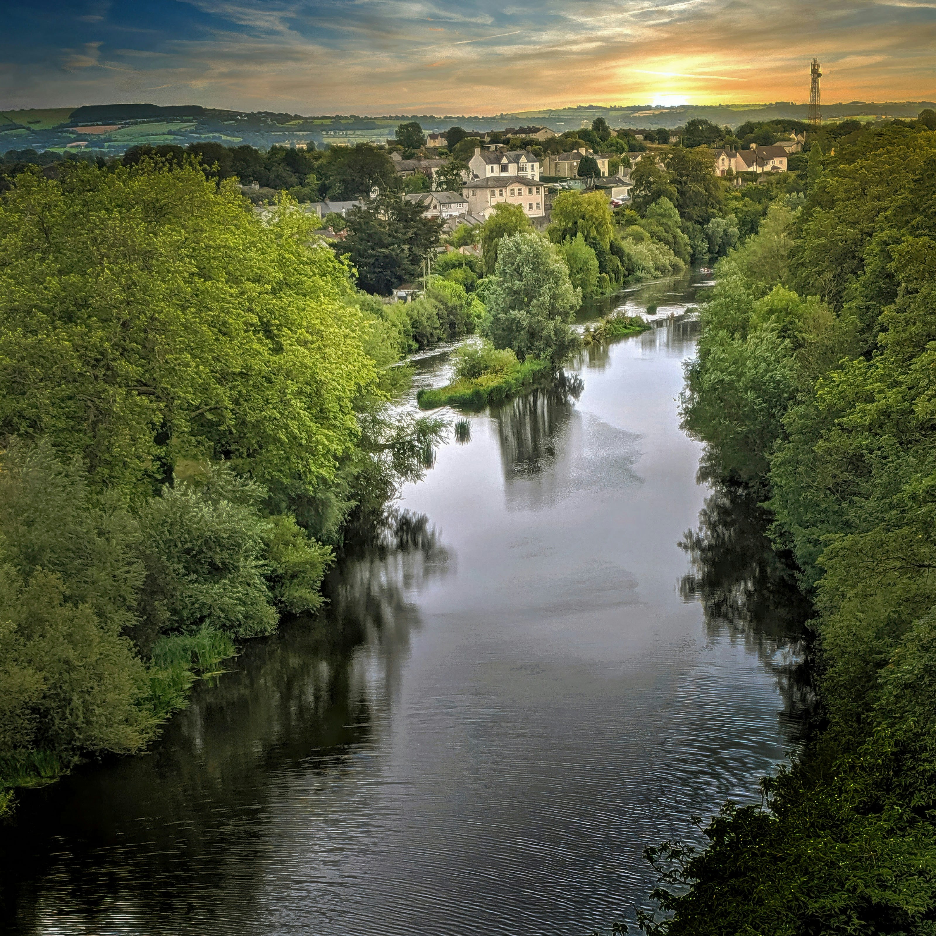 Sunlit River Bend: A Village Quietly Framed by Trees at Dusk